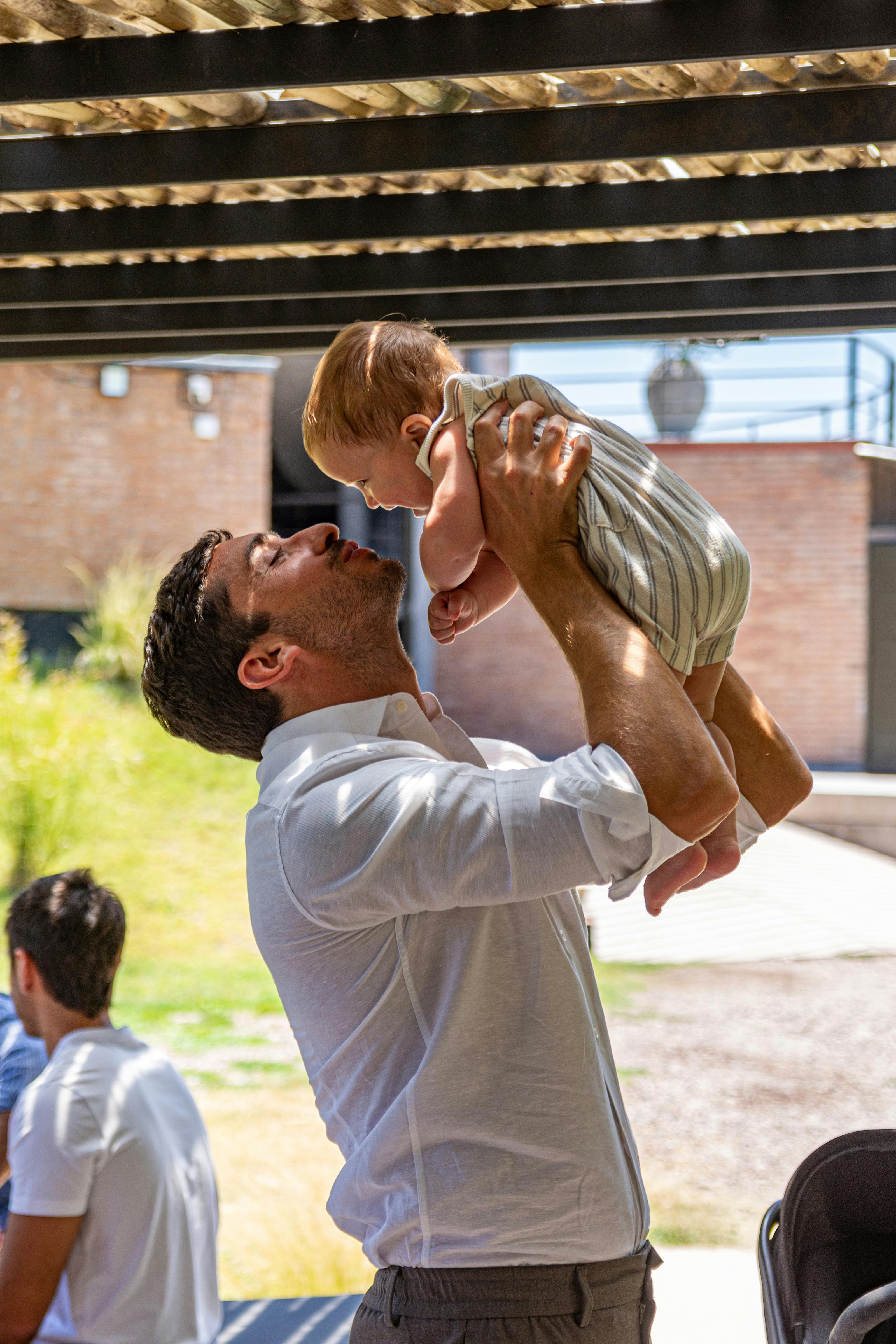 Father Lifting Baby Outdoors in Sunny Setting · Free Stock Photo