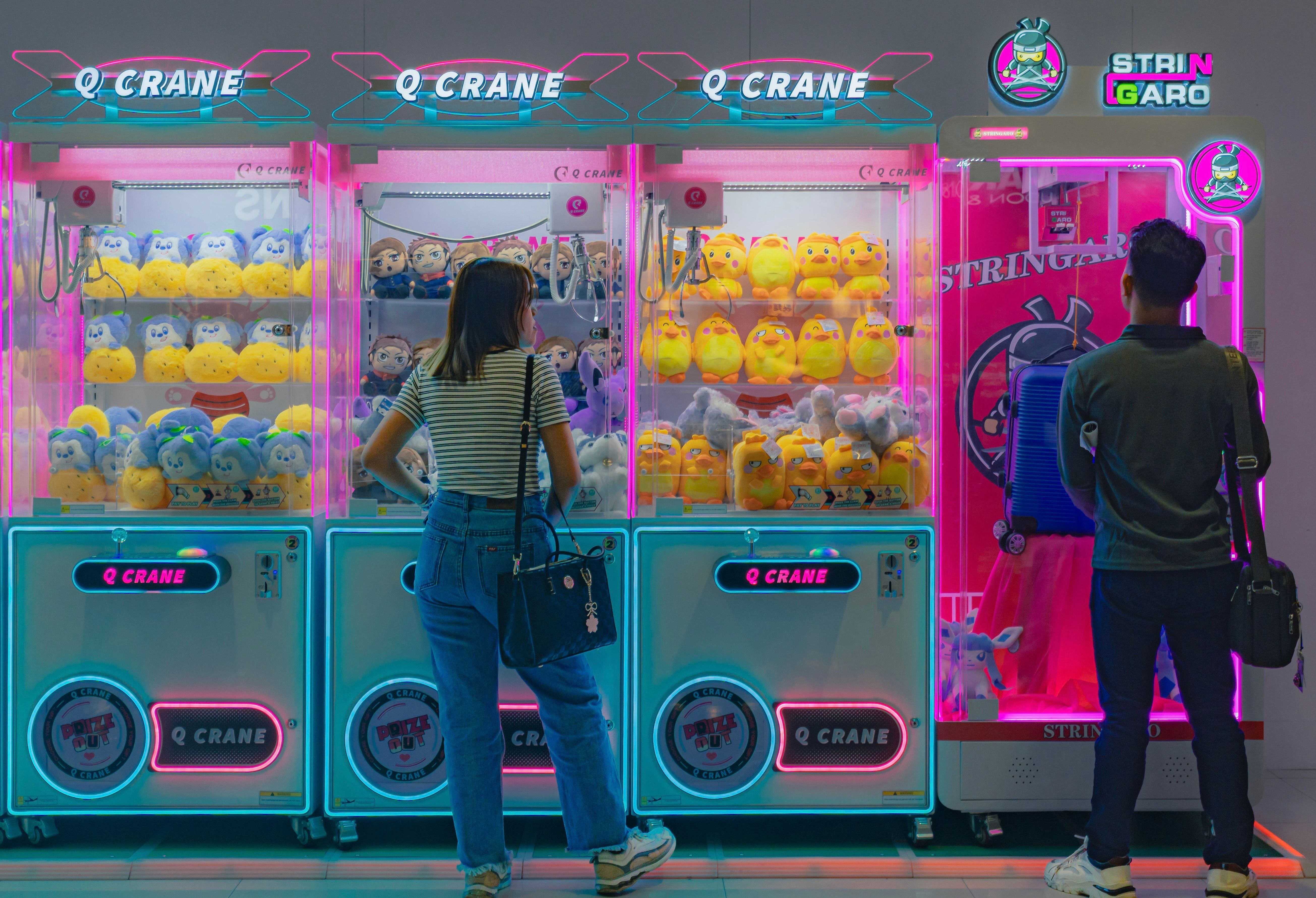 Young people playing colorful claw machines · Free Stock Photo