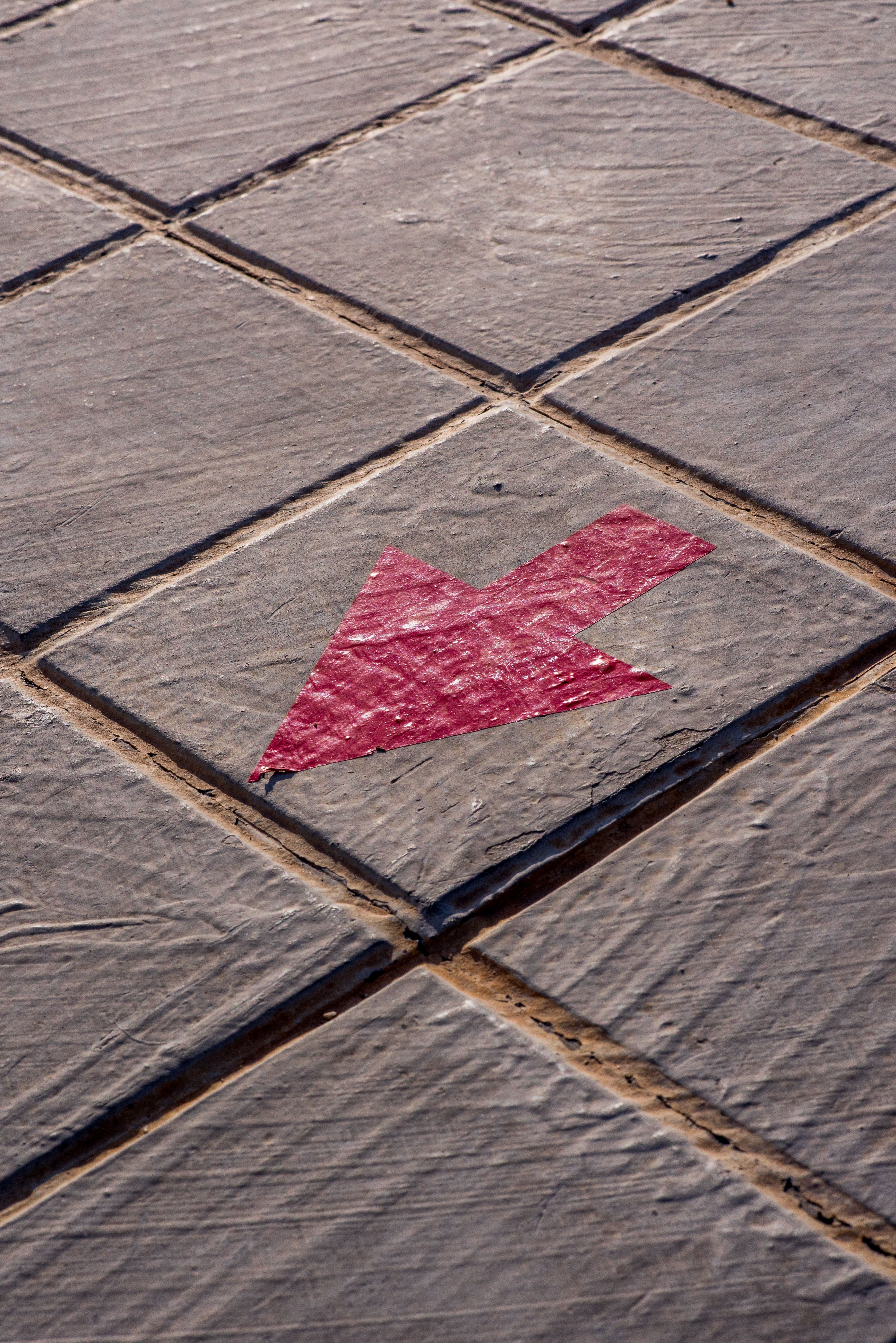 Red Arrow Painted on Concrete Tiles Outdoors · Free Stock Photo