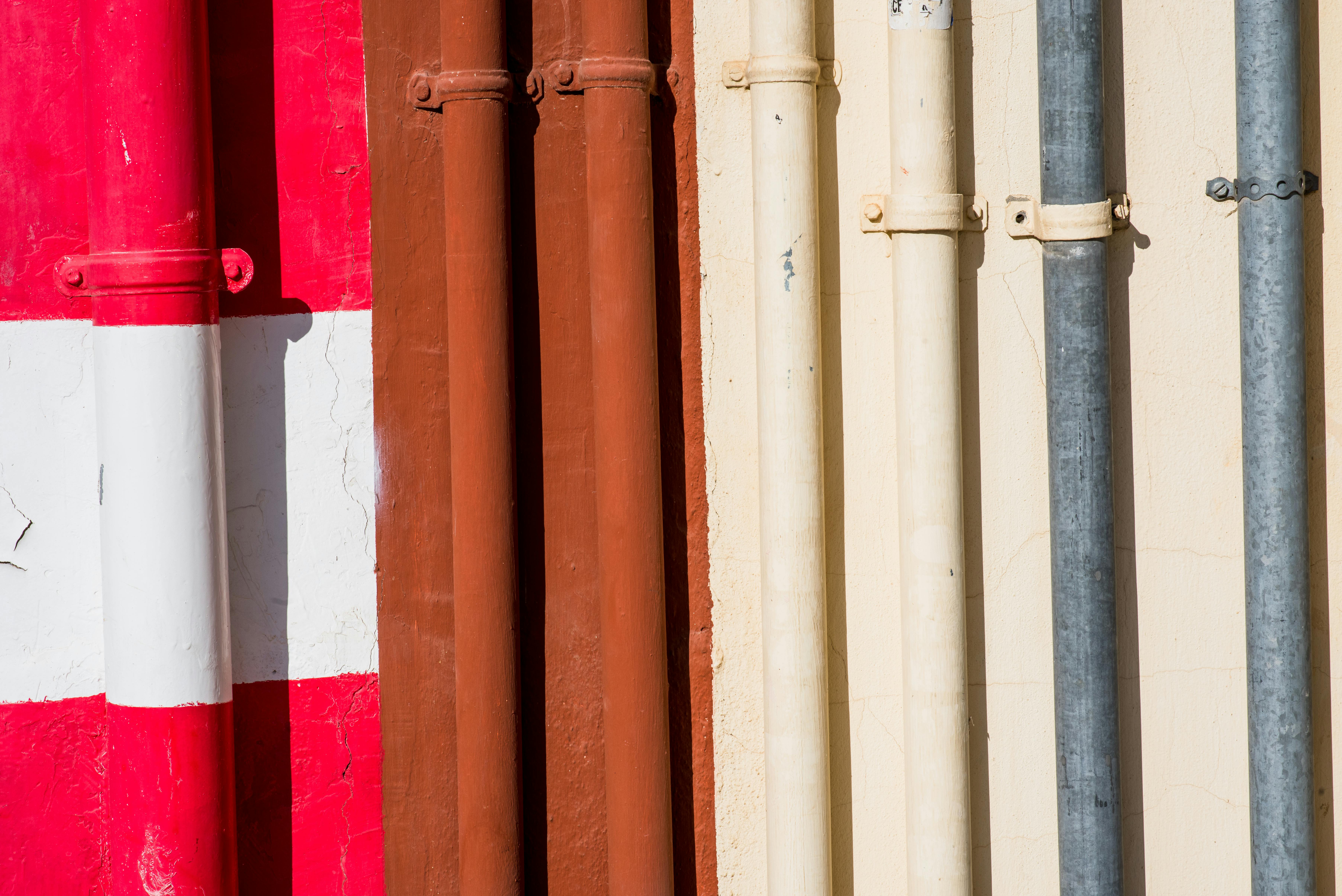 Abstract Vertical Pipes Against Colorful Wall · Free Stock Photo