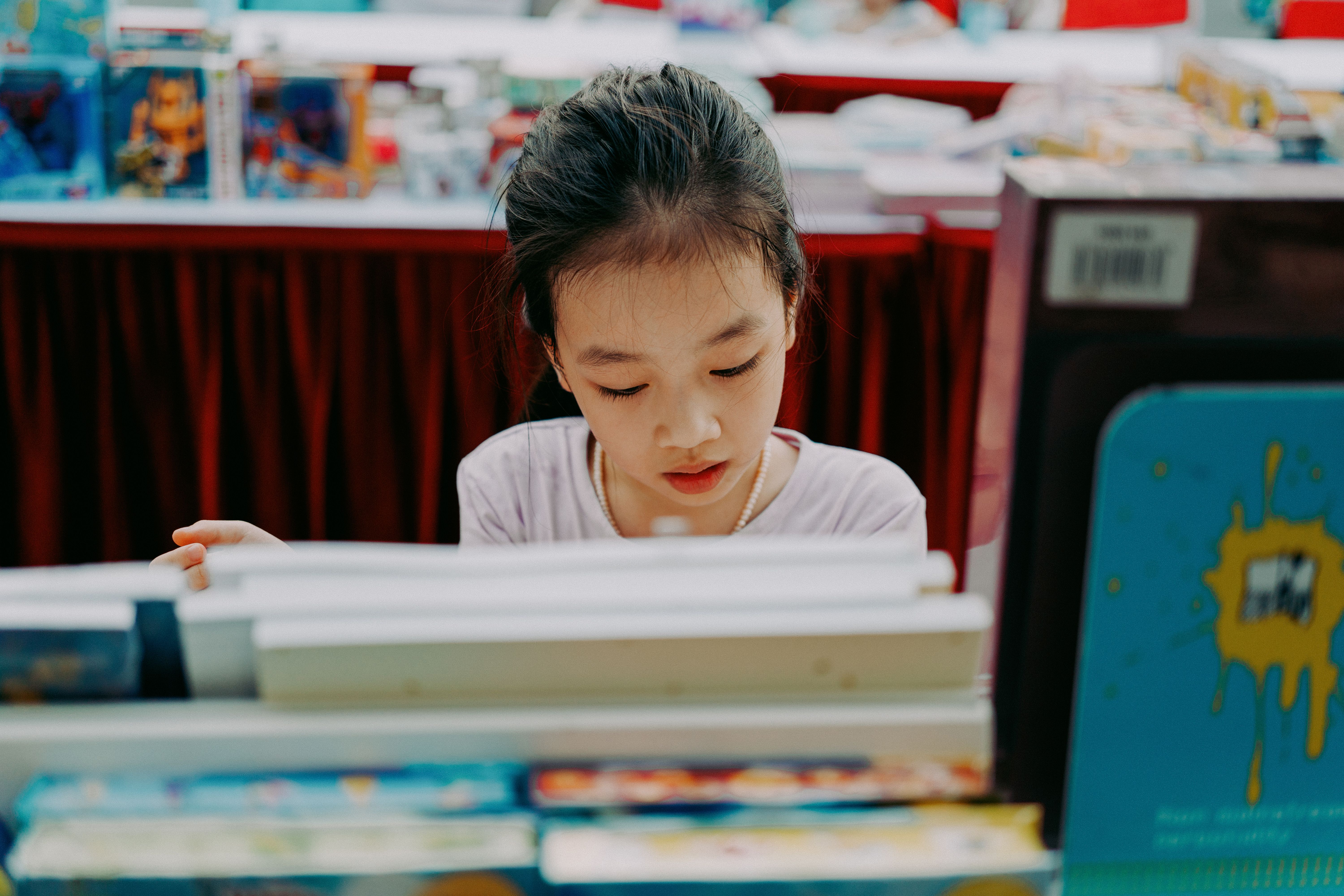 Young Girl Exploring Books at a Fair · Free Stock Photo