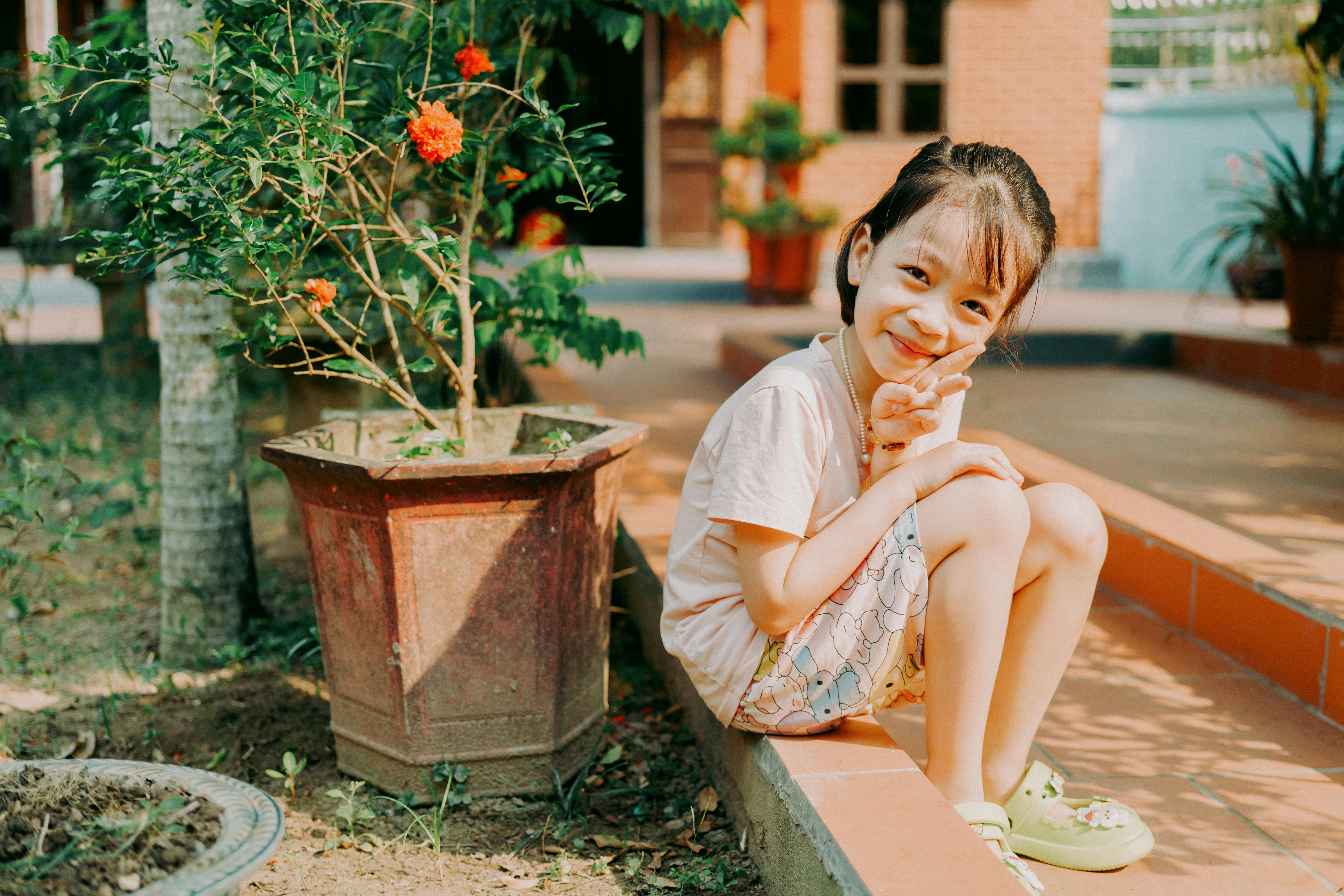 Smiling child sitting outside in sunny garden · Free Stock Photo