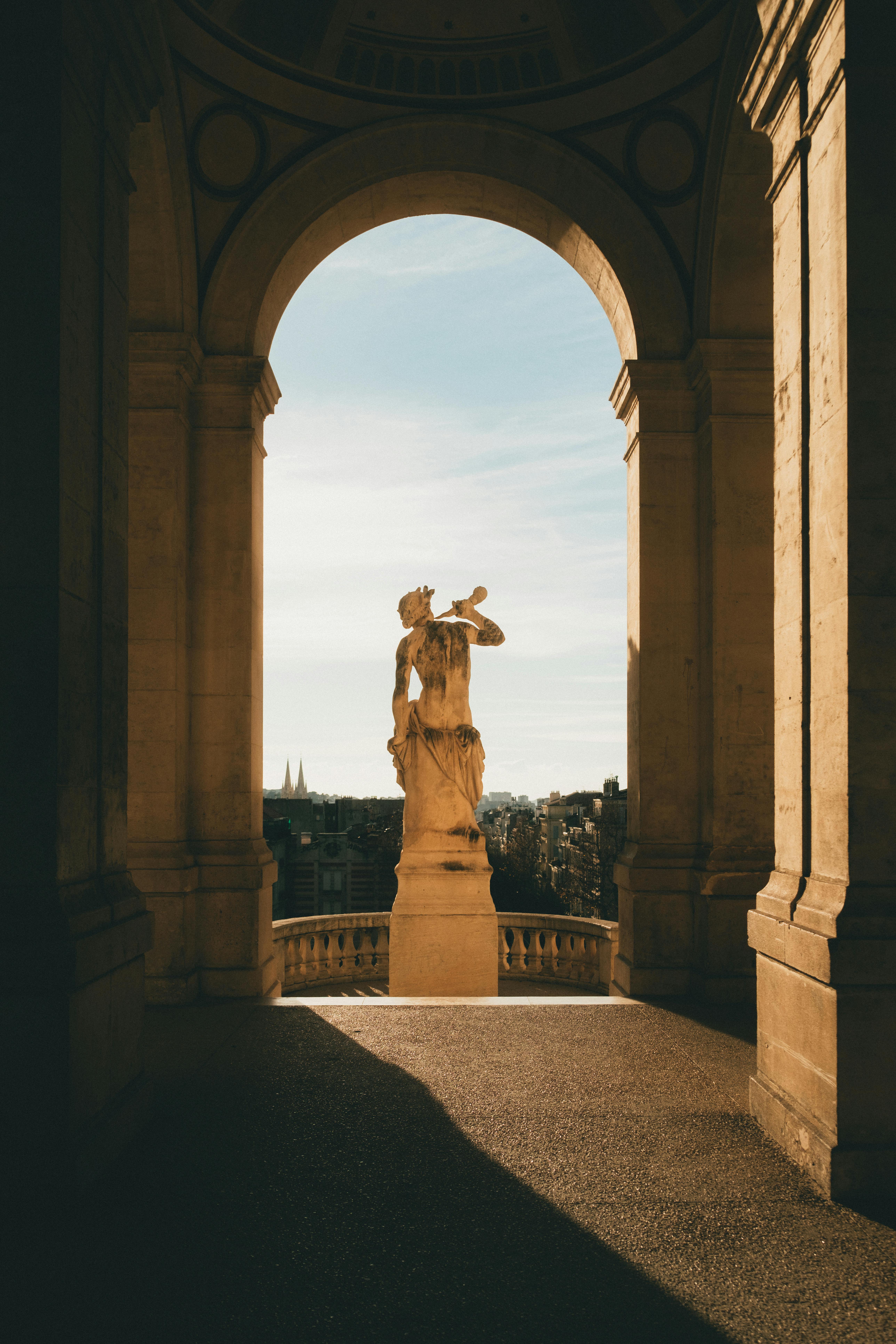 Statue Framed by Architectural Archway at Sunset · Free Stock Photo