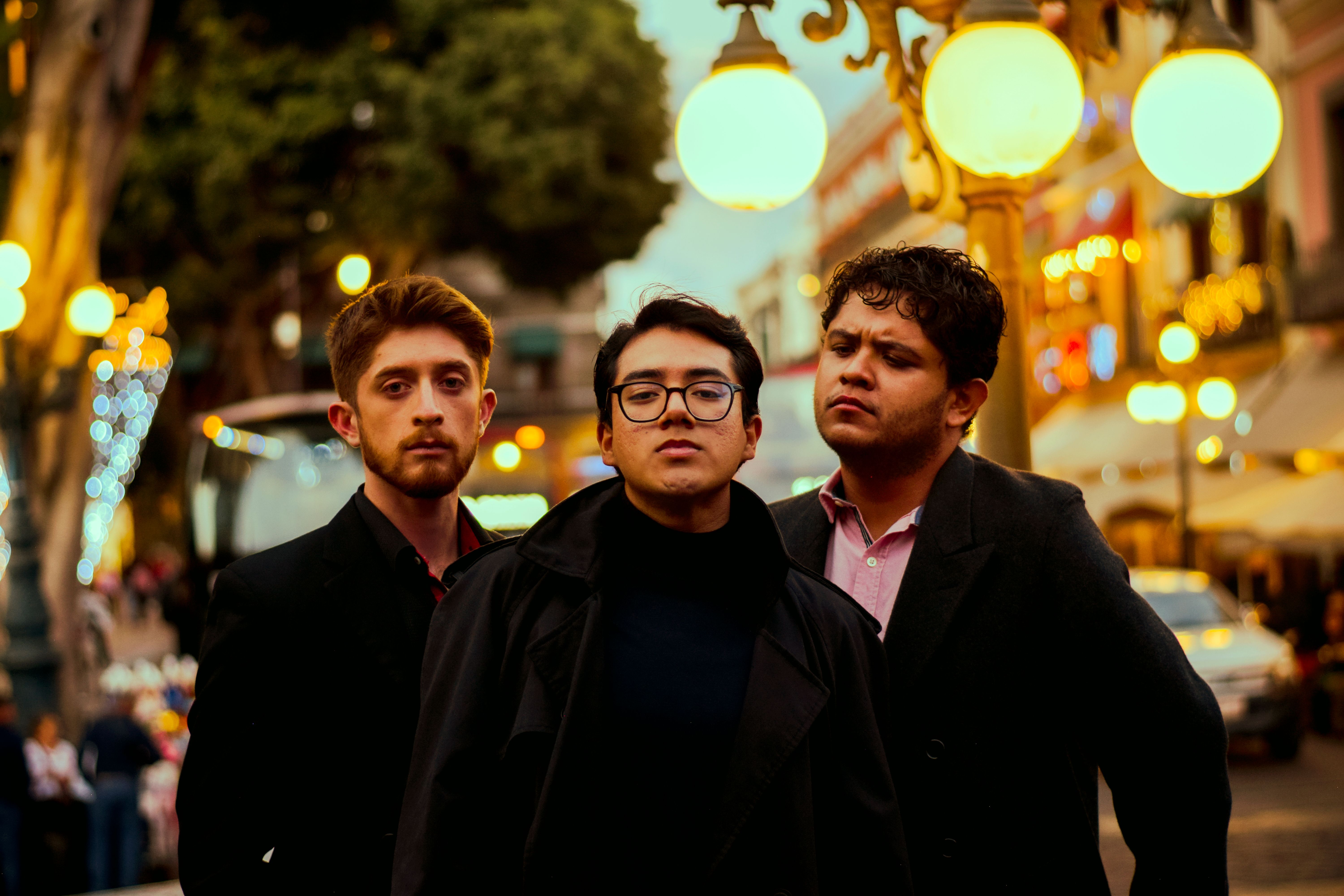 Three Men Posing on a Lively Street at Night · Free Stock Photo