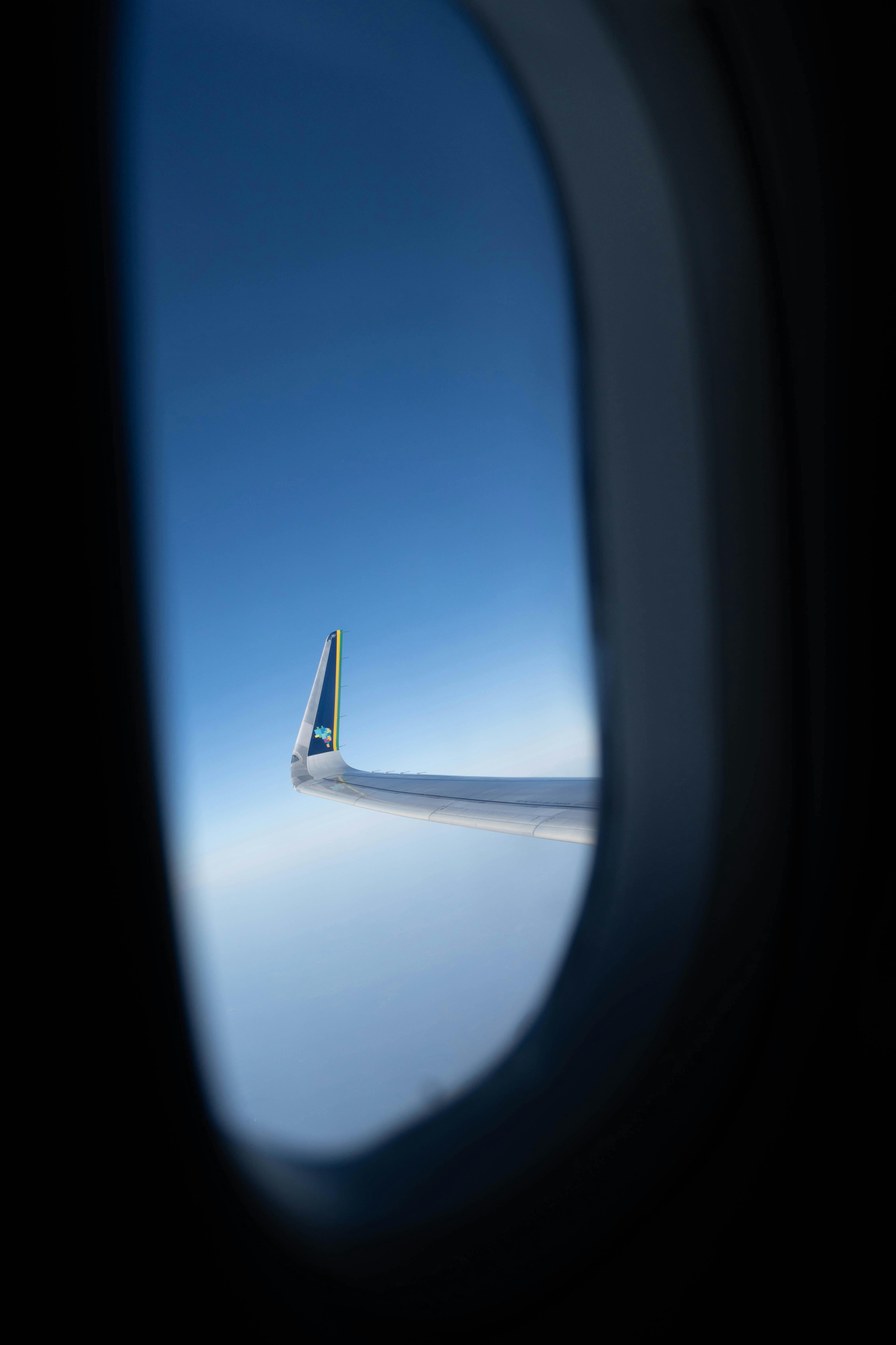 View from an Airplane Window Showing a Wing · Free Stock Photo