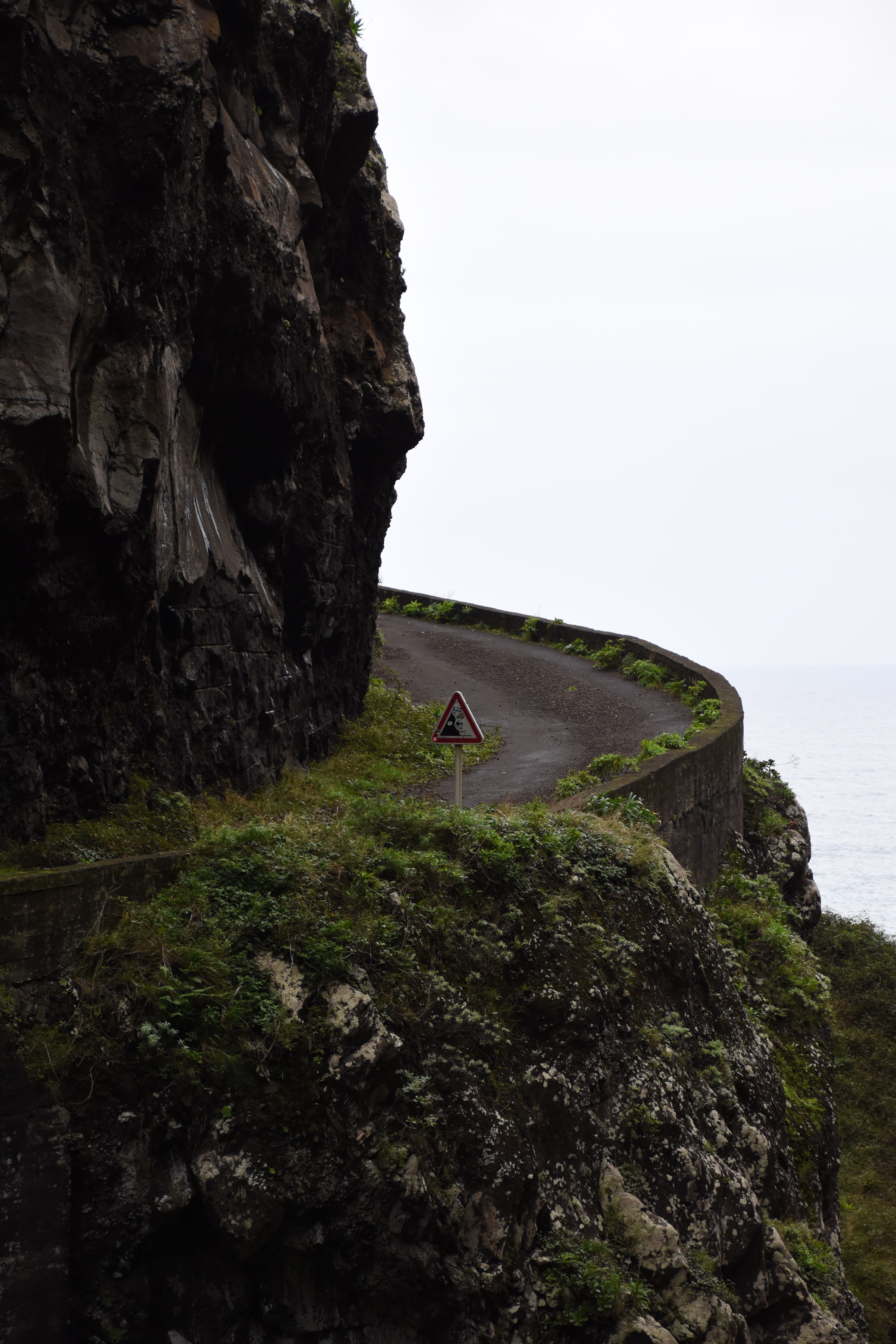 Dramatic Coastal Cliffside Road with Warning Sign · Free Stock Photo
