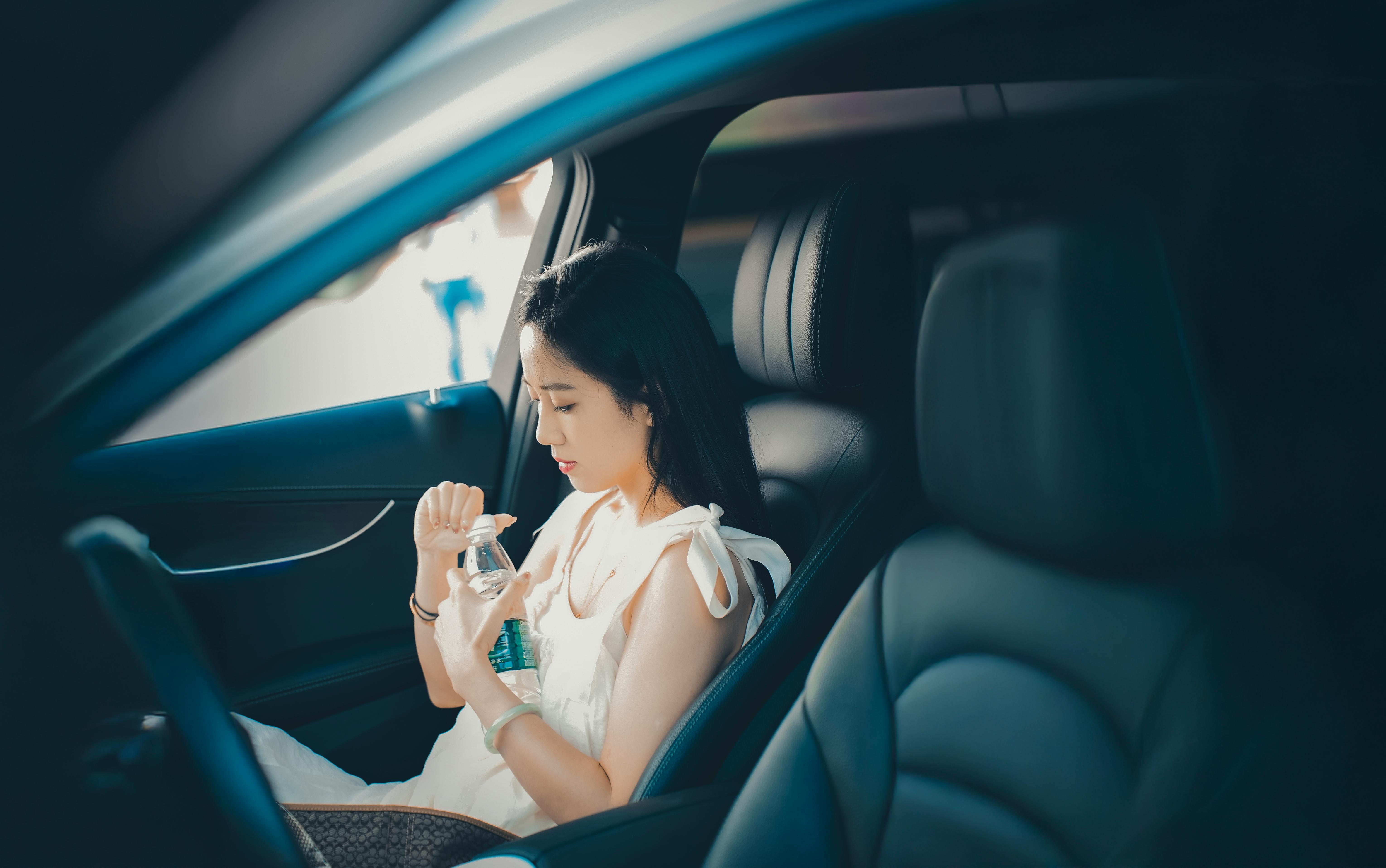 Woman Drinking Water Inside a Luxury Car · Free Stock Photo