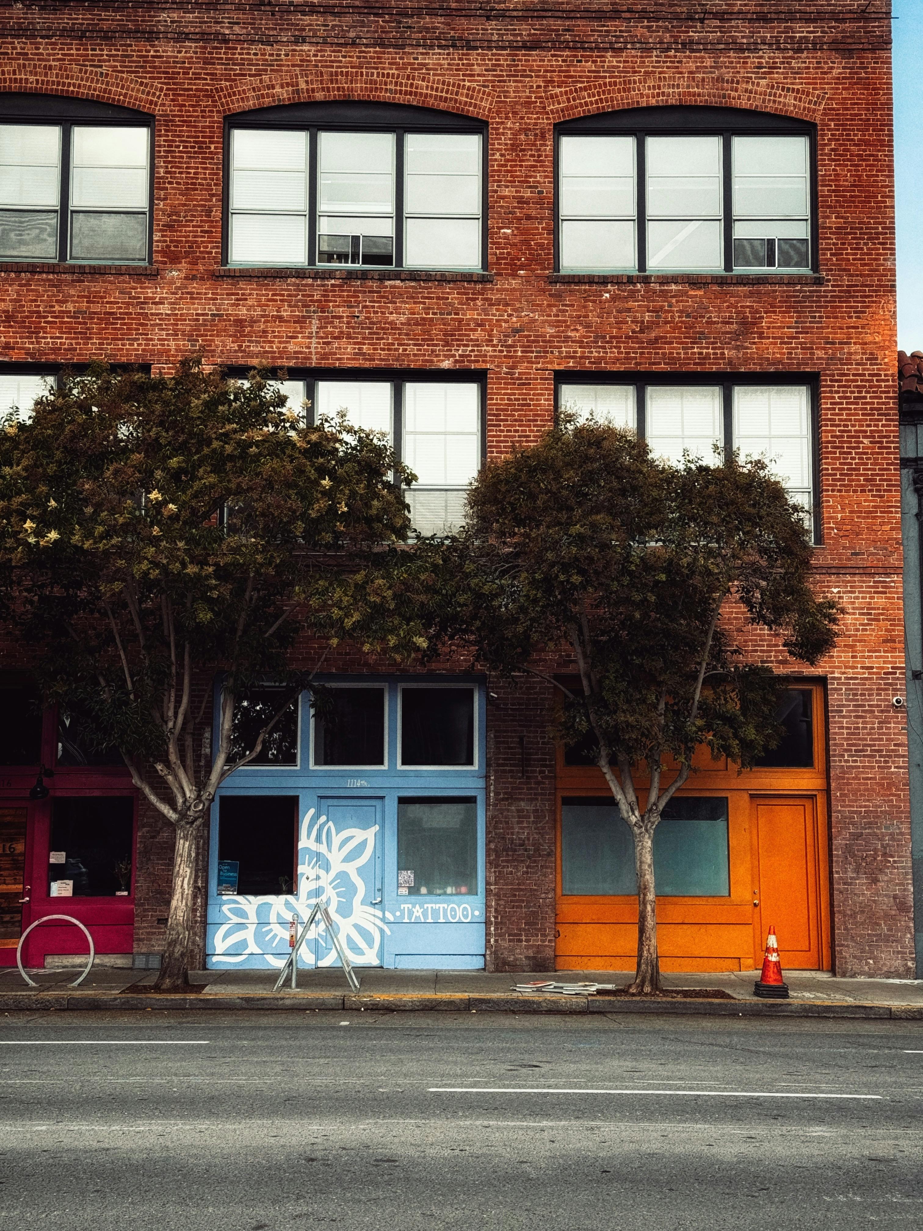 Brick Building with Vibrant Storefronts on City Street · Free Stock Photo