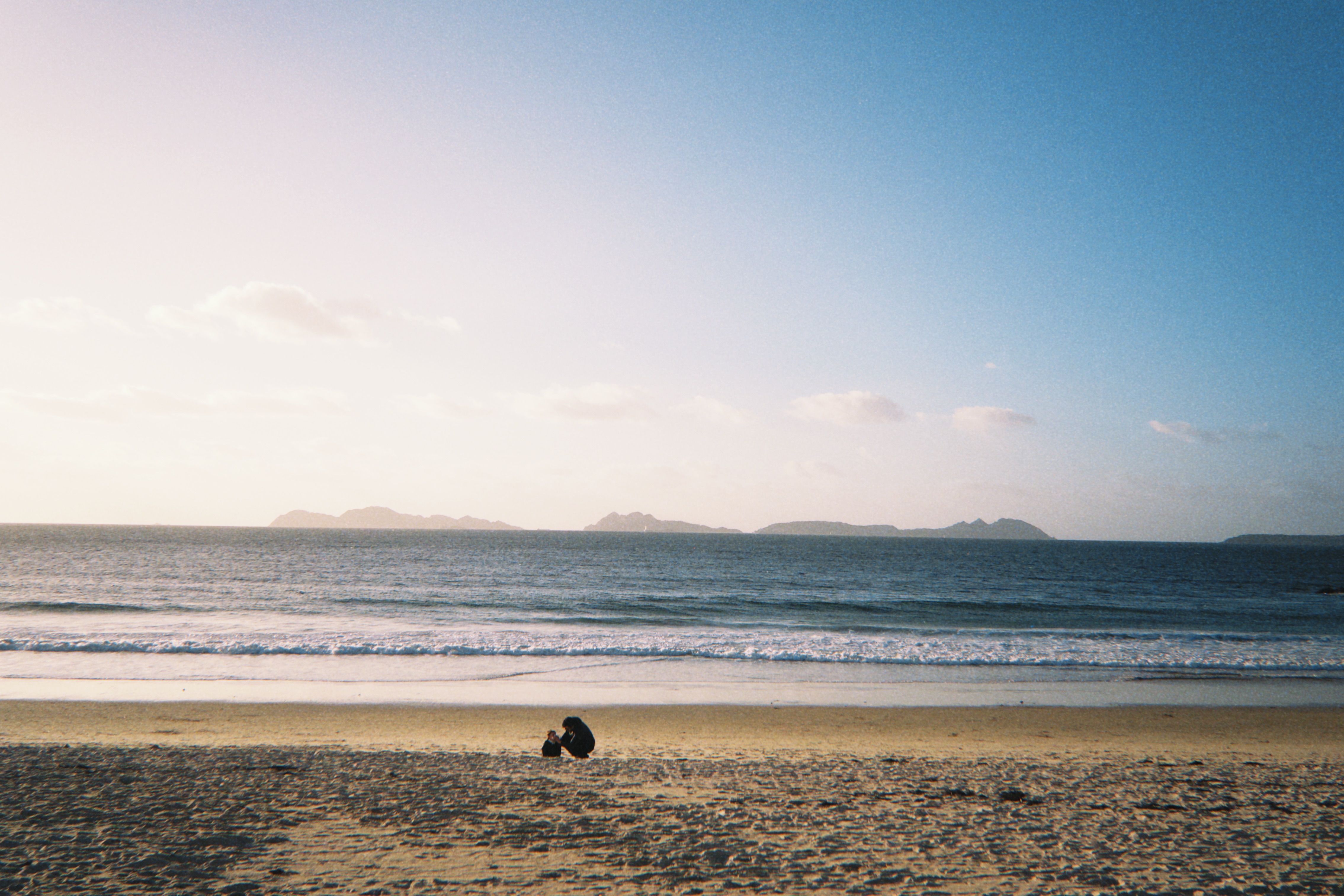 Serene Beach Scene with Lone Figure at Sunset · Free Stock Photo