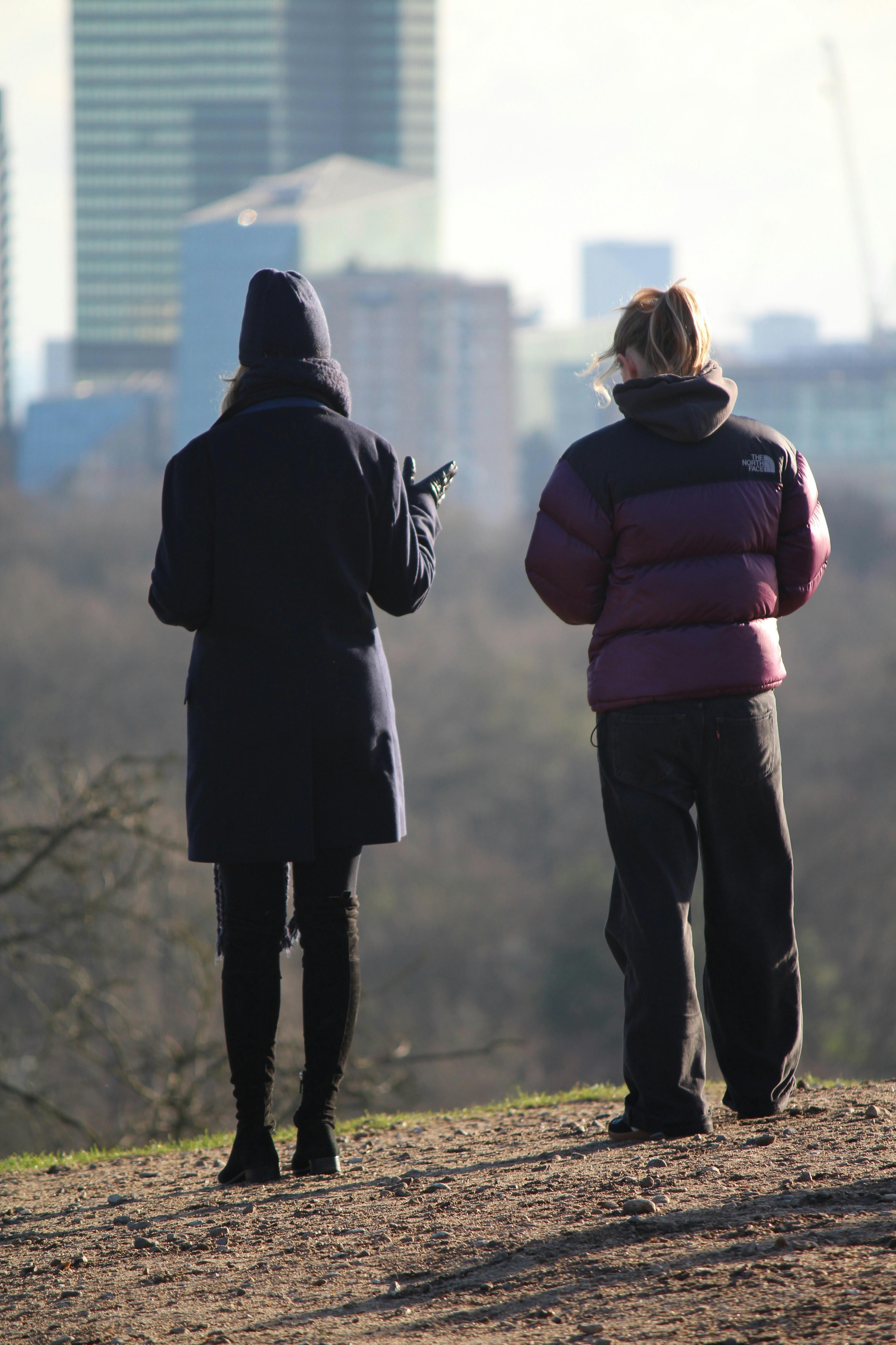 Two people observing cityscape from park hill · Free Stock Photo