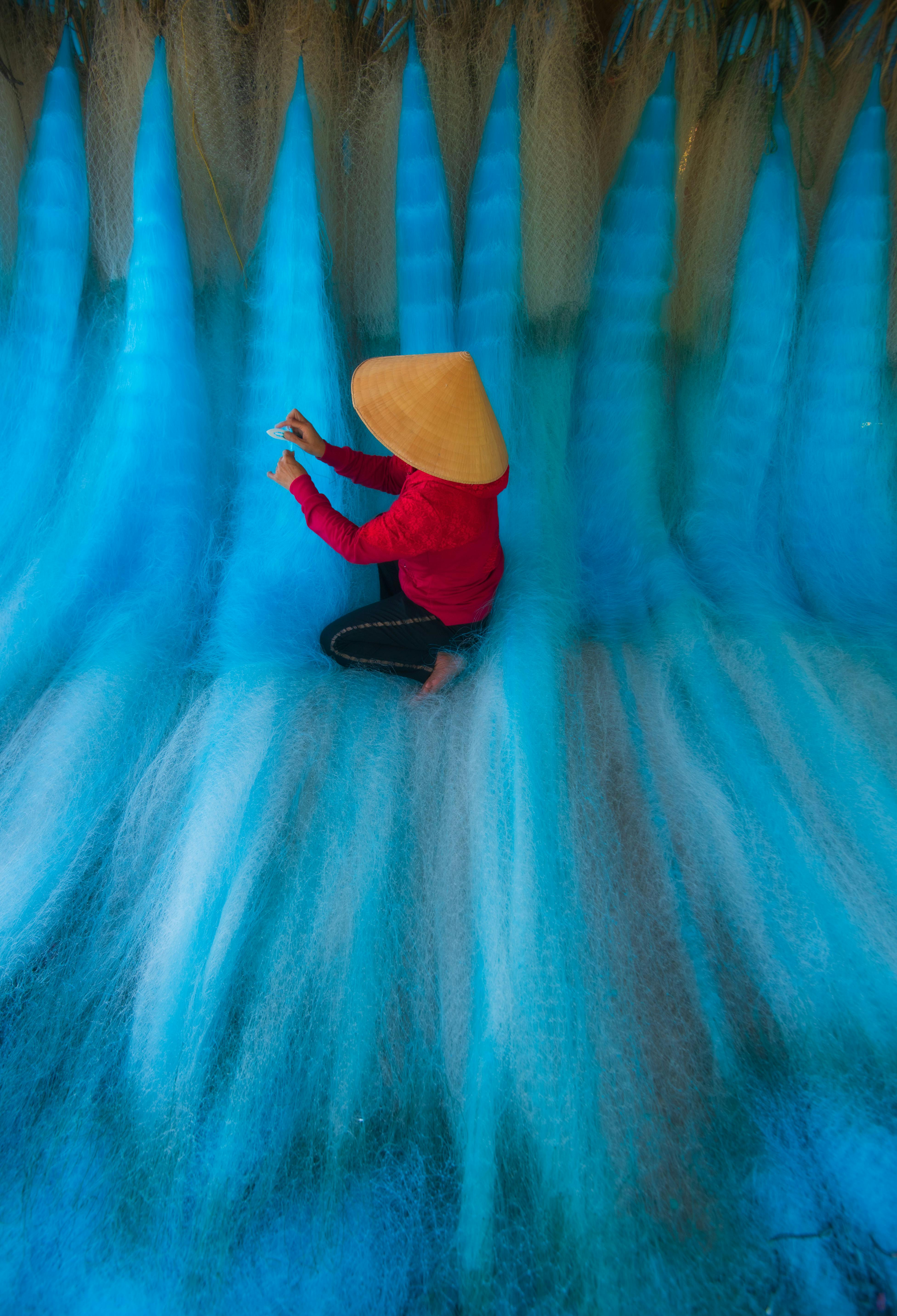 Fisherman Weaving Nets in Vibrant Blue Environment · Free Stock Photo