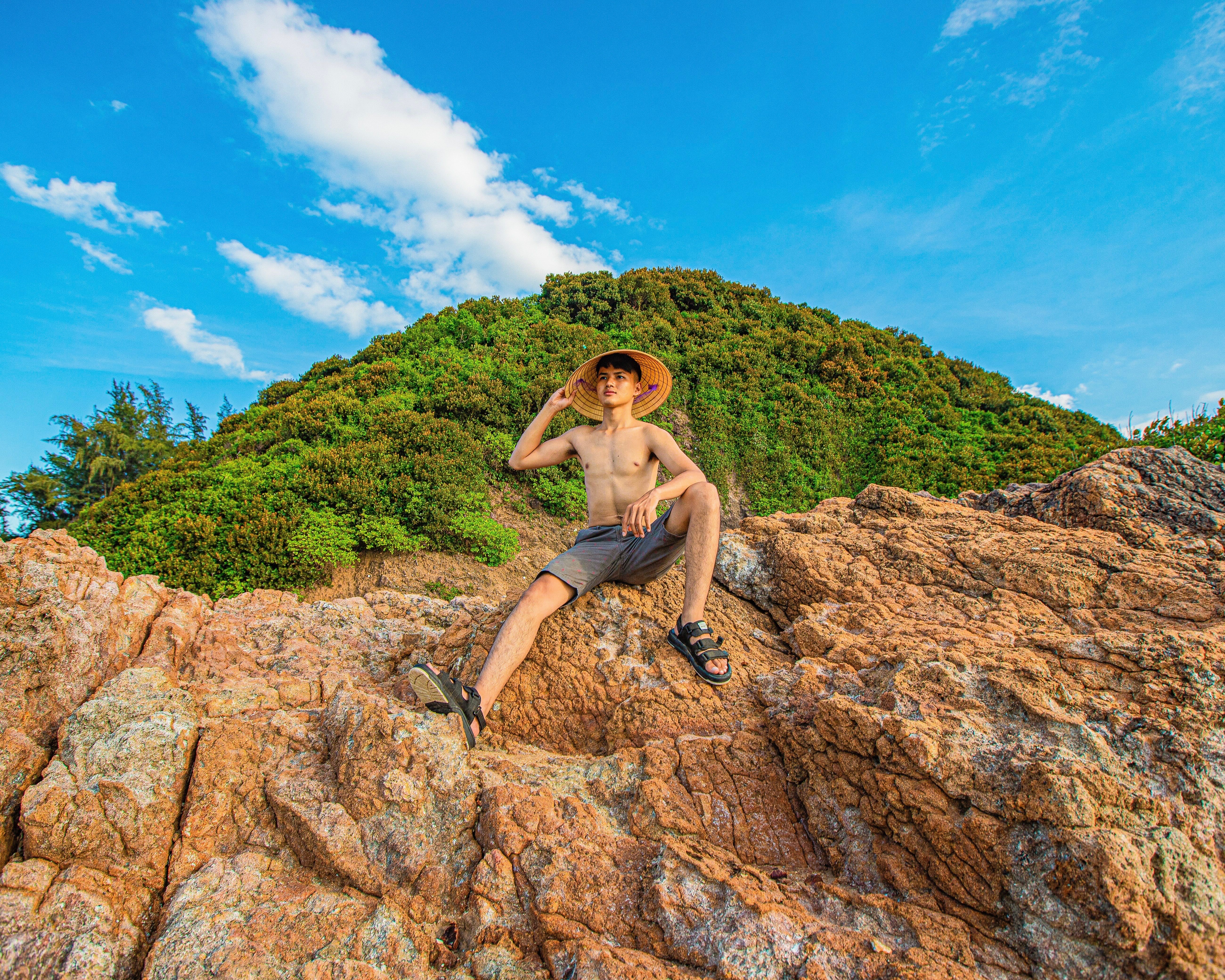 Young Man Wearing Straw Hat on Rocky Landscape · Free Stock Photo