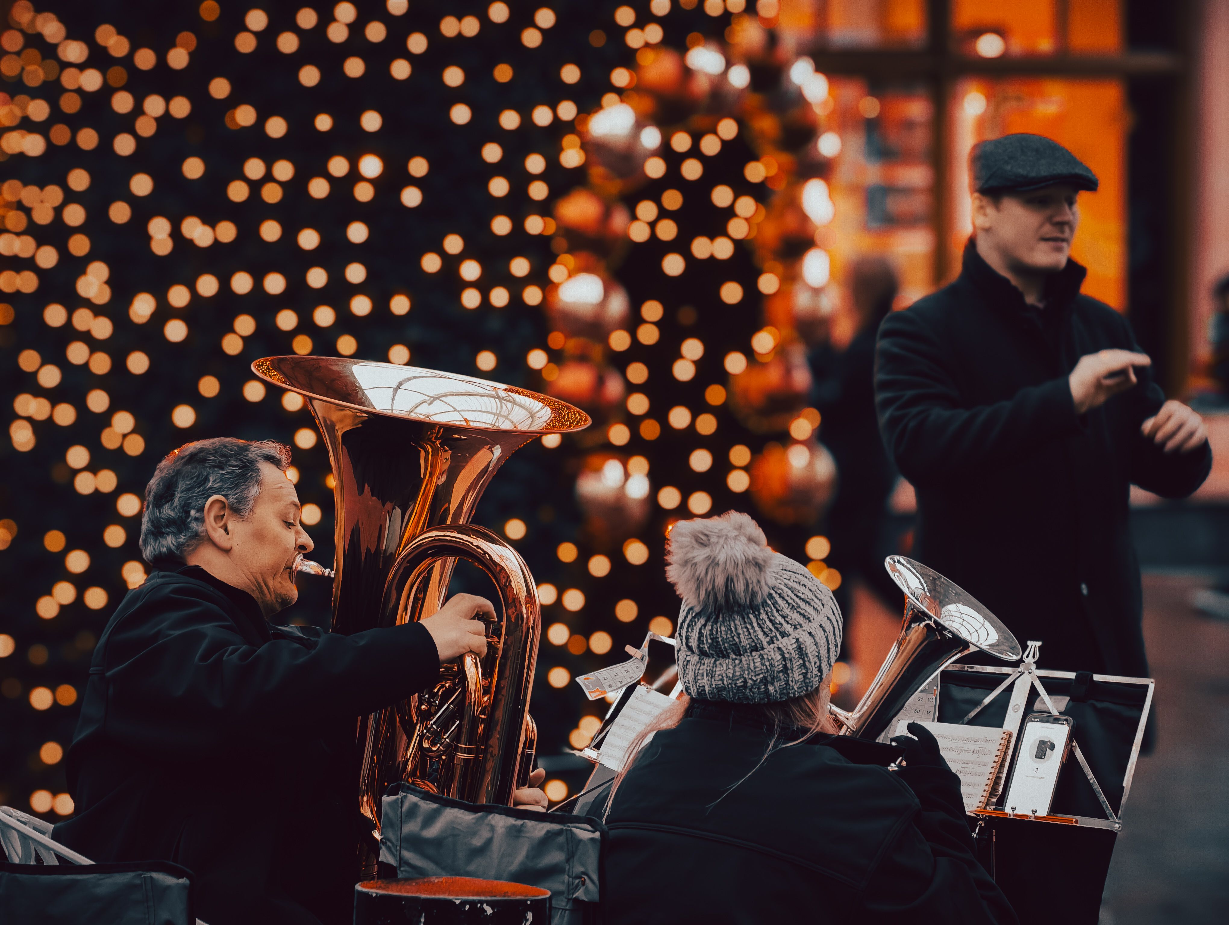 Festive Street Musicians Performing in Holiday Lights · Free Stock Photo