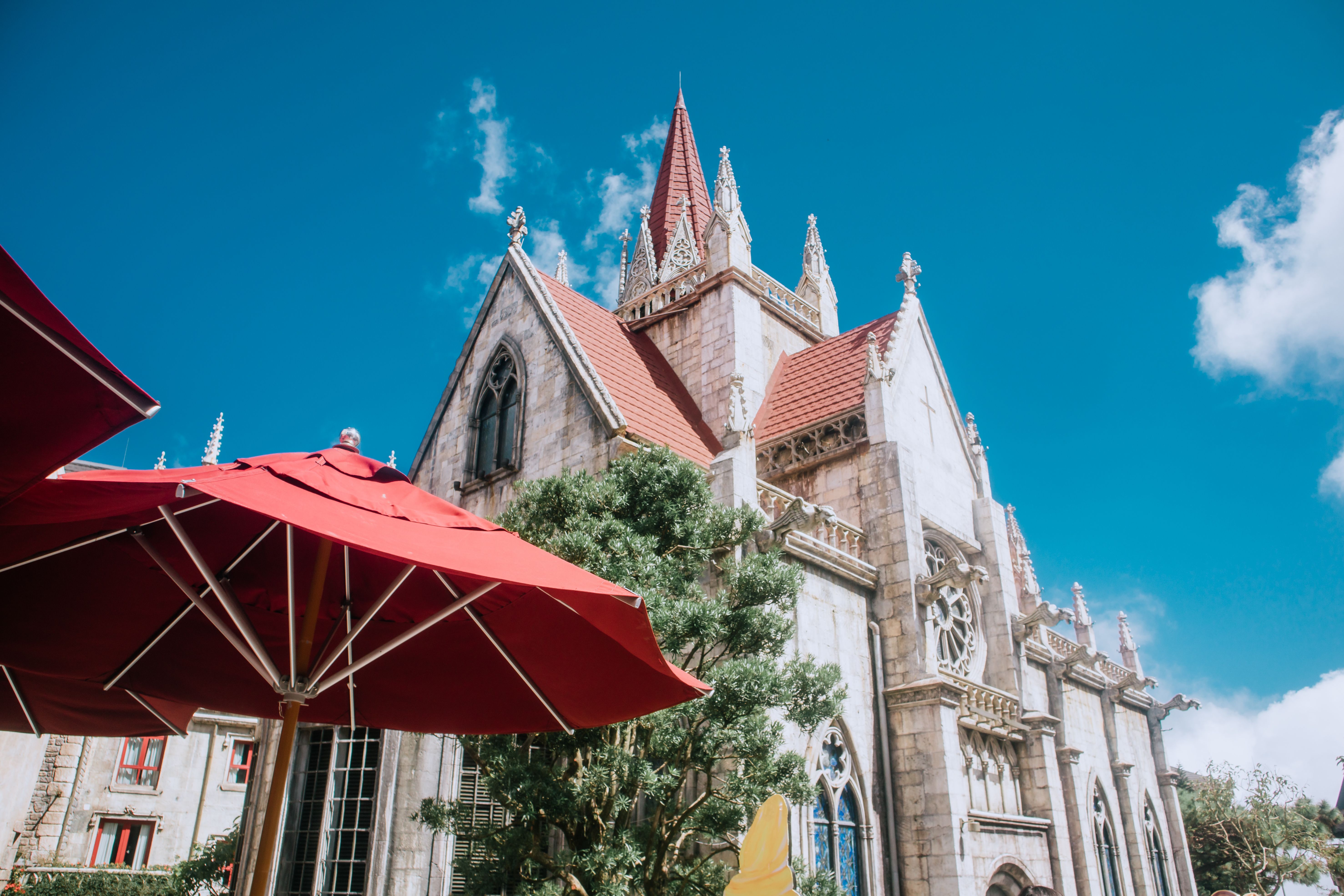 Gothic Church with Red Umbrellas Against Clear Sky · Free Stock Photo