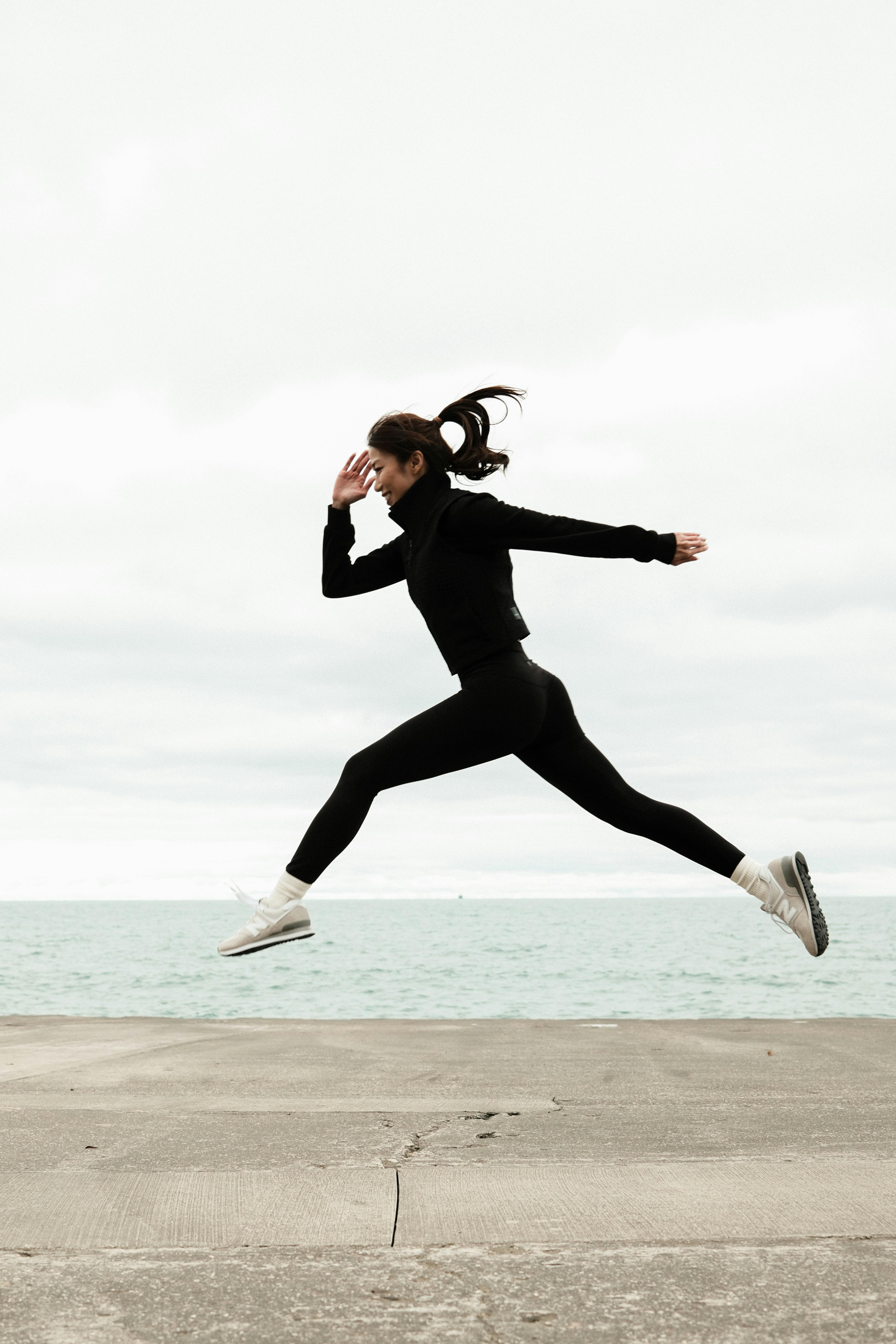 Dynamic Woman Leaping by Ocean in Winter · Free Stock Photo