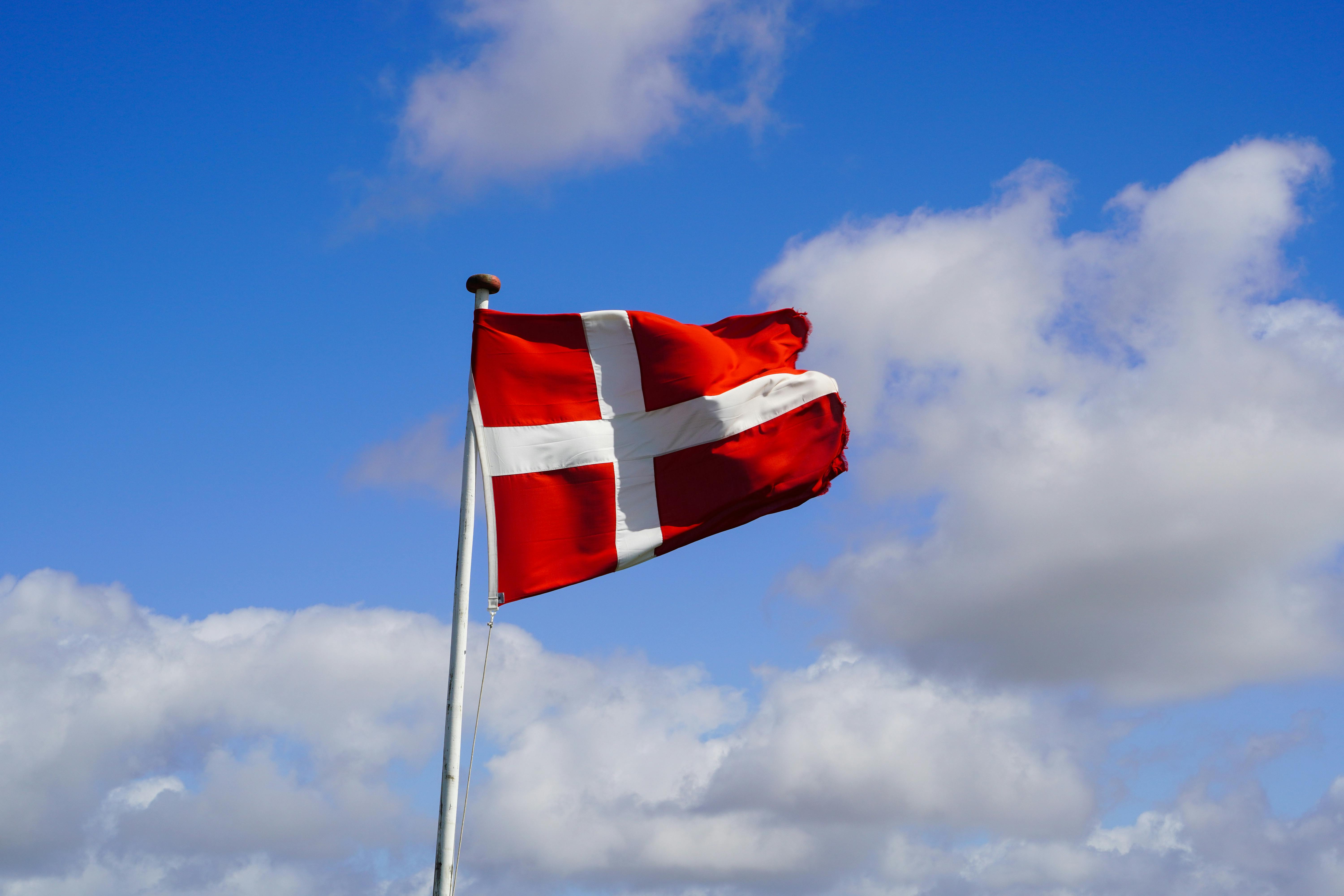 Danish Flag Waving Against Blue Sky and Clouds · Free Stock Photo
