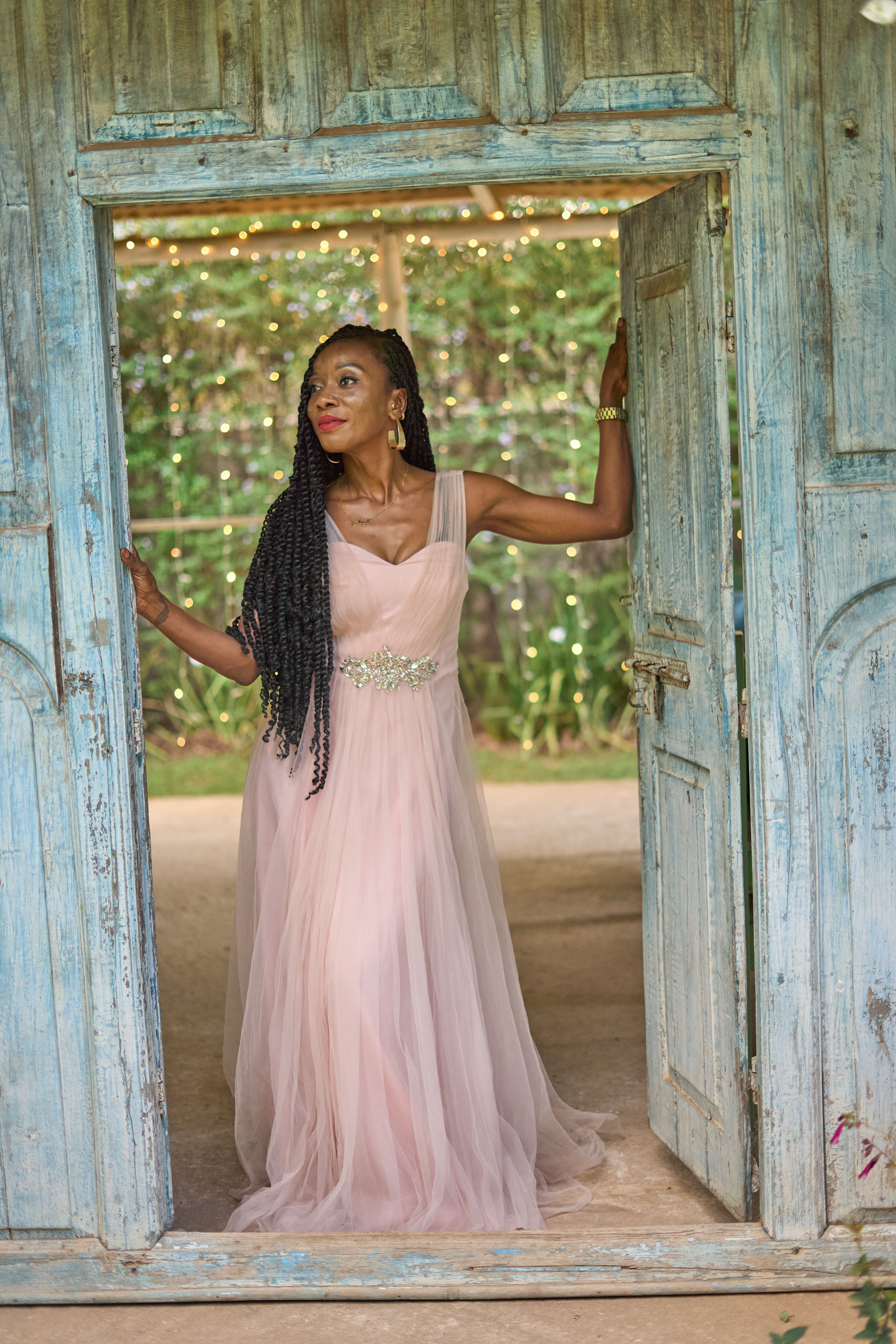 Elegant Woman in Flowing Pink Gown at Rustic Doorway · Free Stock Photo
