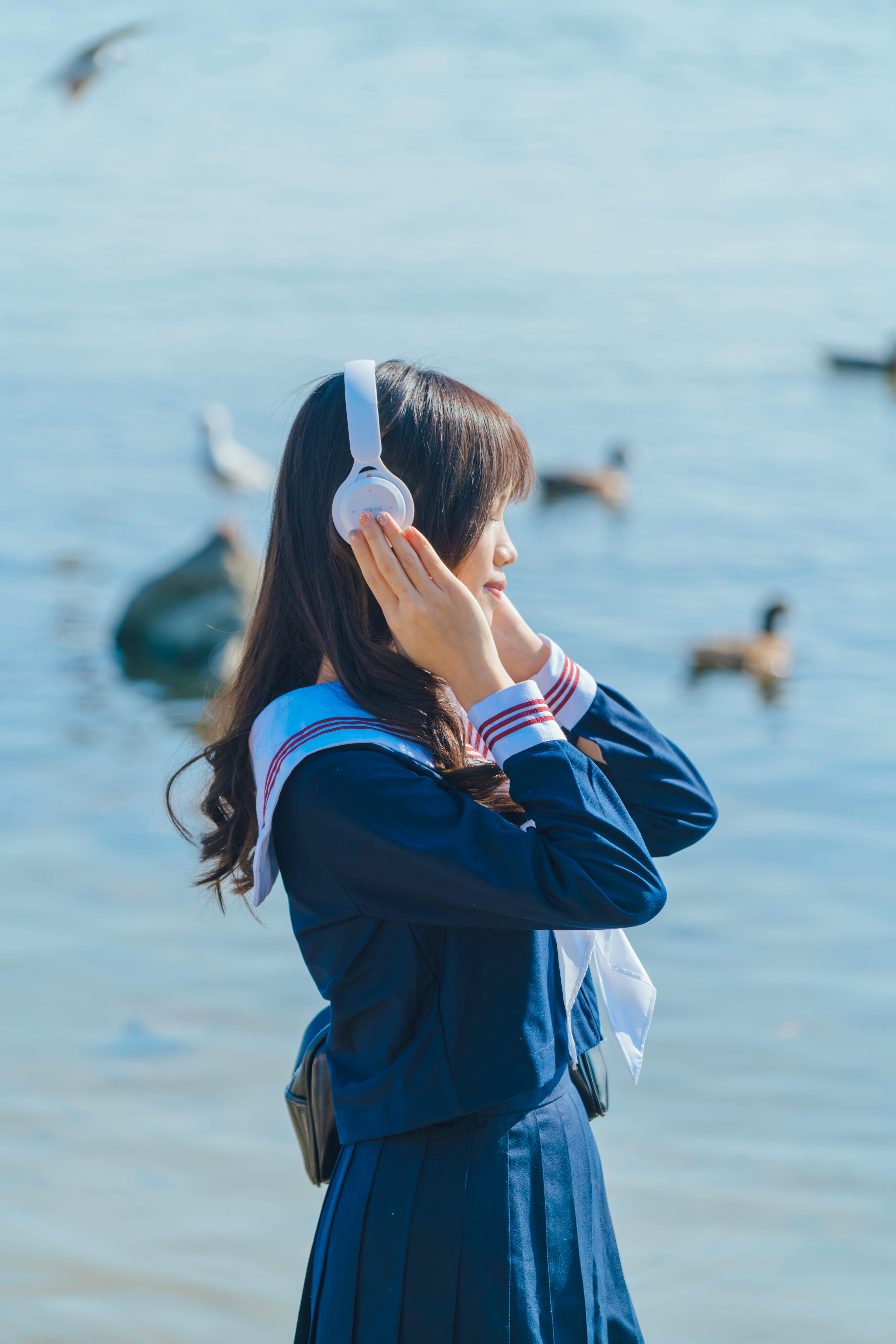 Teen Girl in Sailor Suit Enjoying Music by the Water · Free Stock Photo