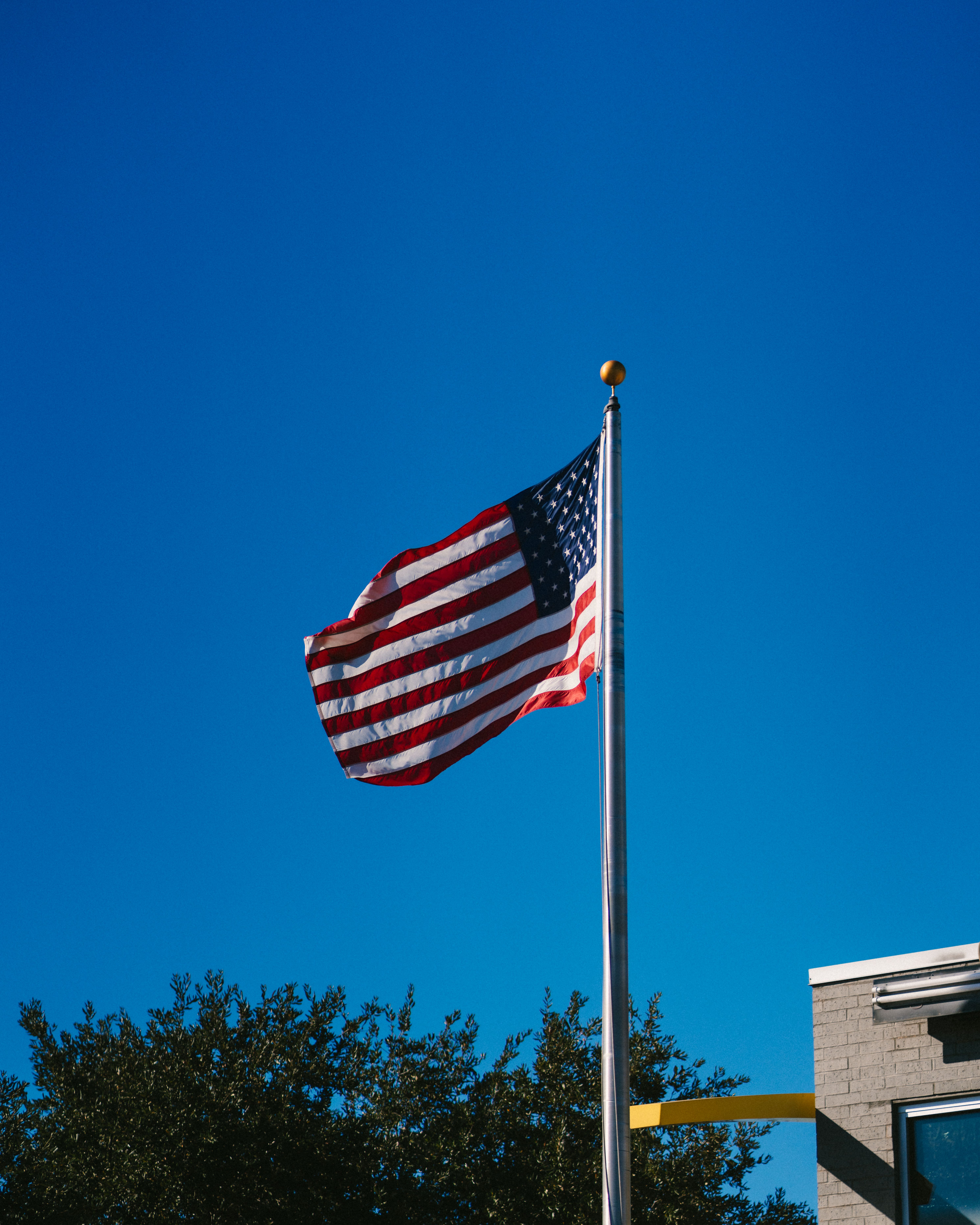 American Flag Waving in Bright Blue Sky · Free Stock Photo
