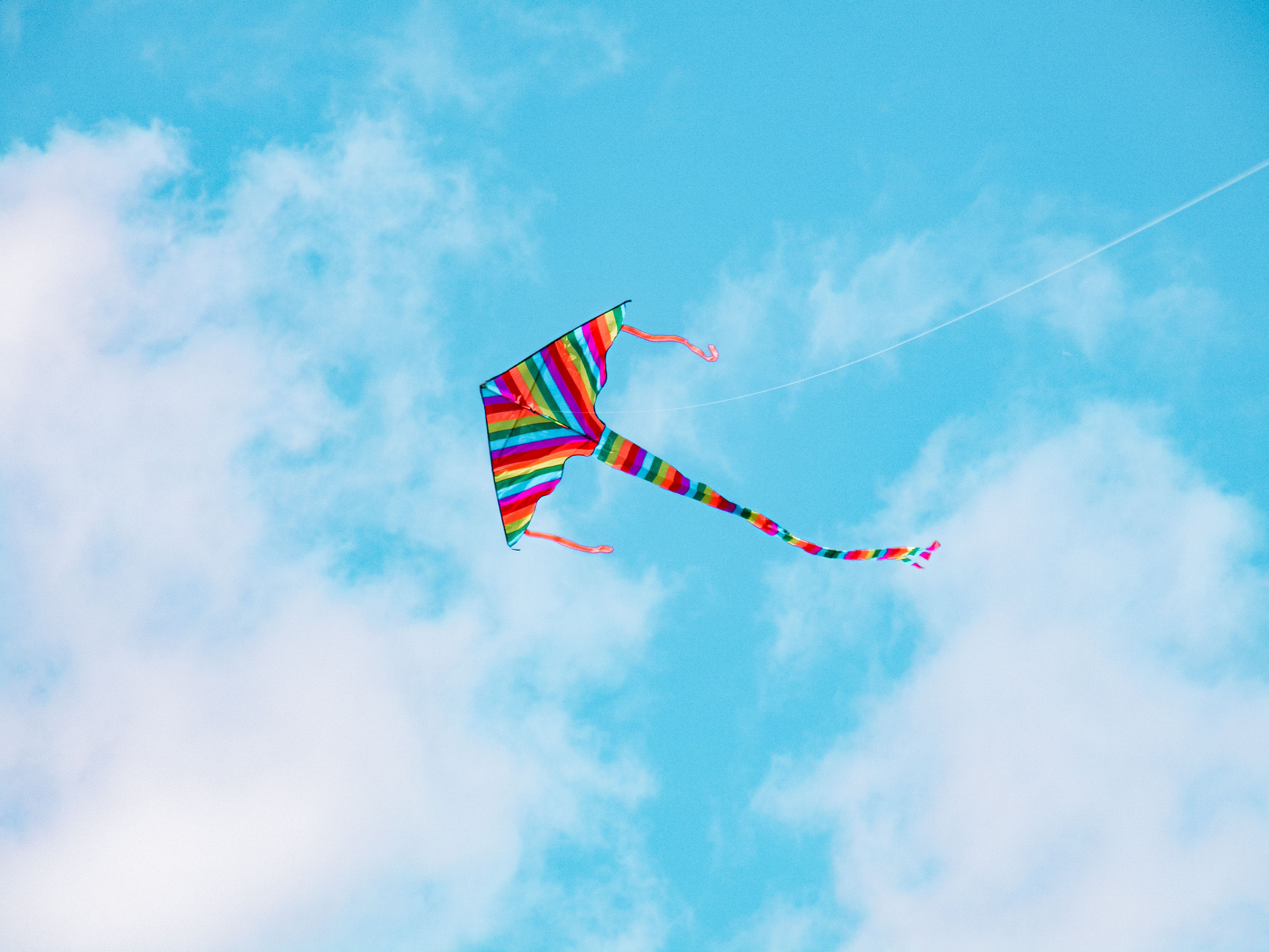 Colorful Kite Flying in Blue Sky with Clouds · Free Stock Photo