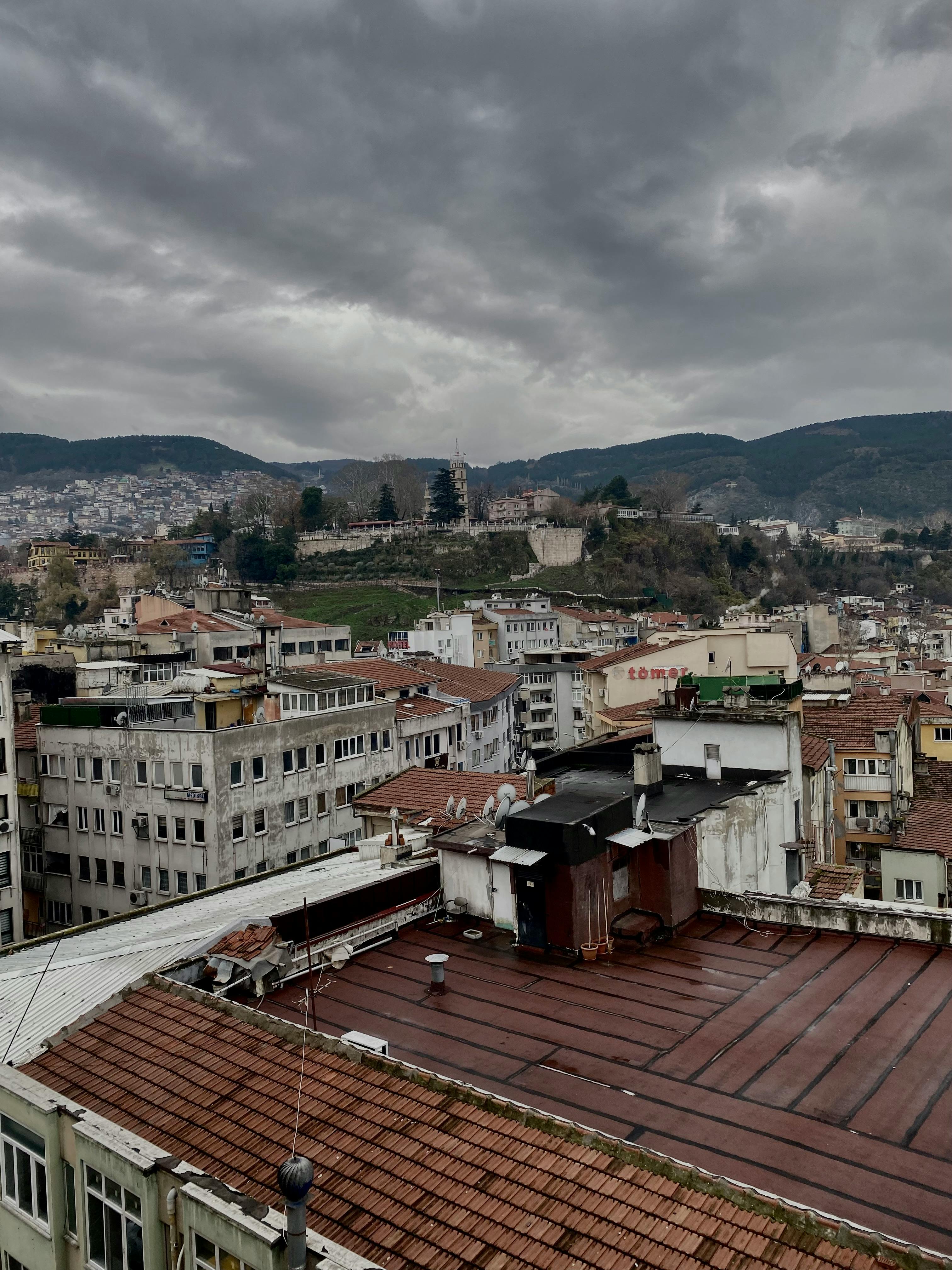 Overcast View of Urban Rooftops and Distant Mountains · Free Stock Photo