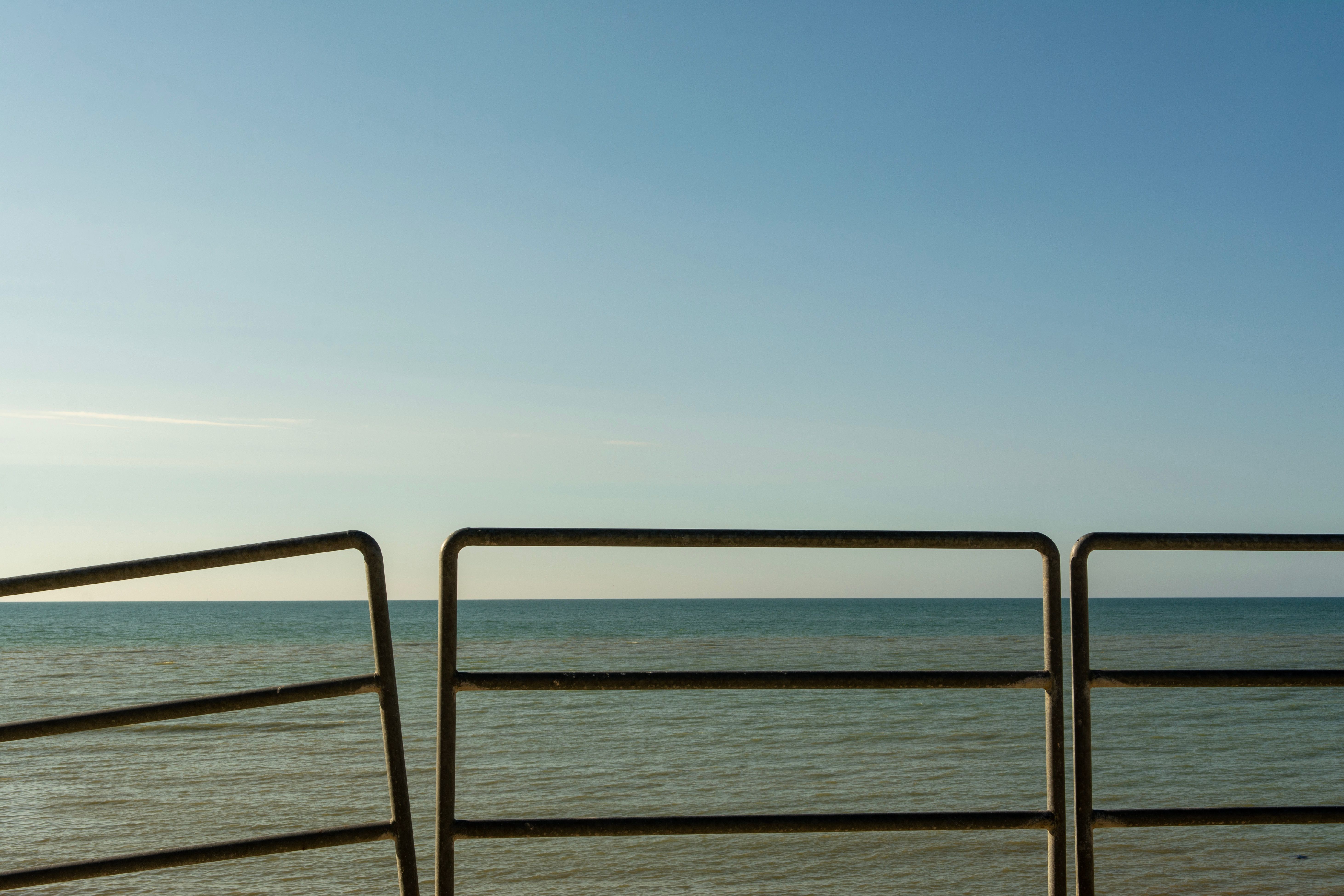 Tranquil Ocean View Behind a Metal Fence · Free Stock Photo