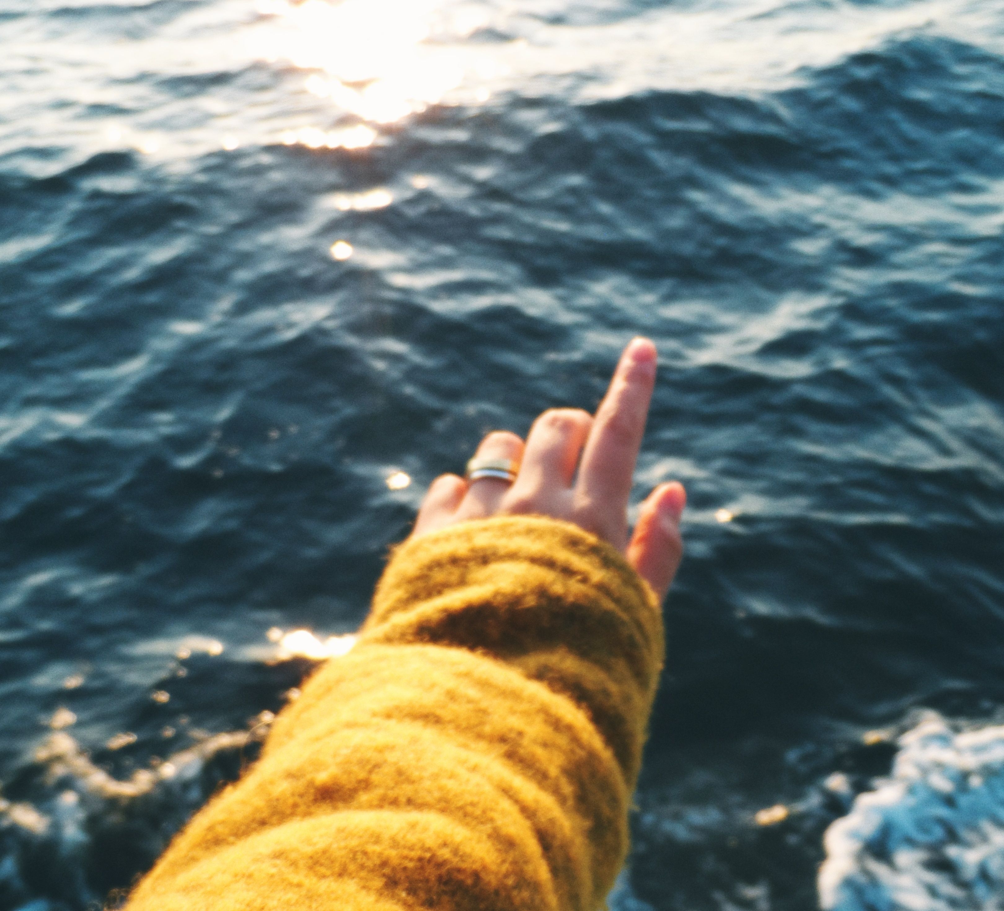 Outstretched hand over ocean waves in sunlight · Free Stock Photo