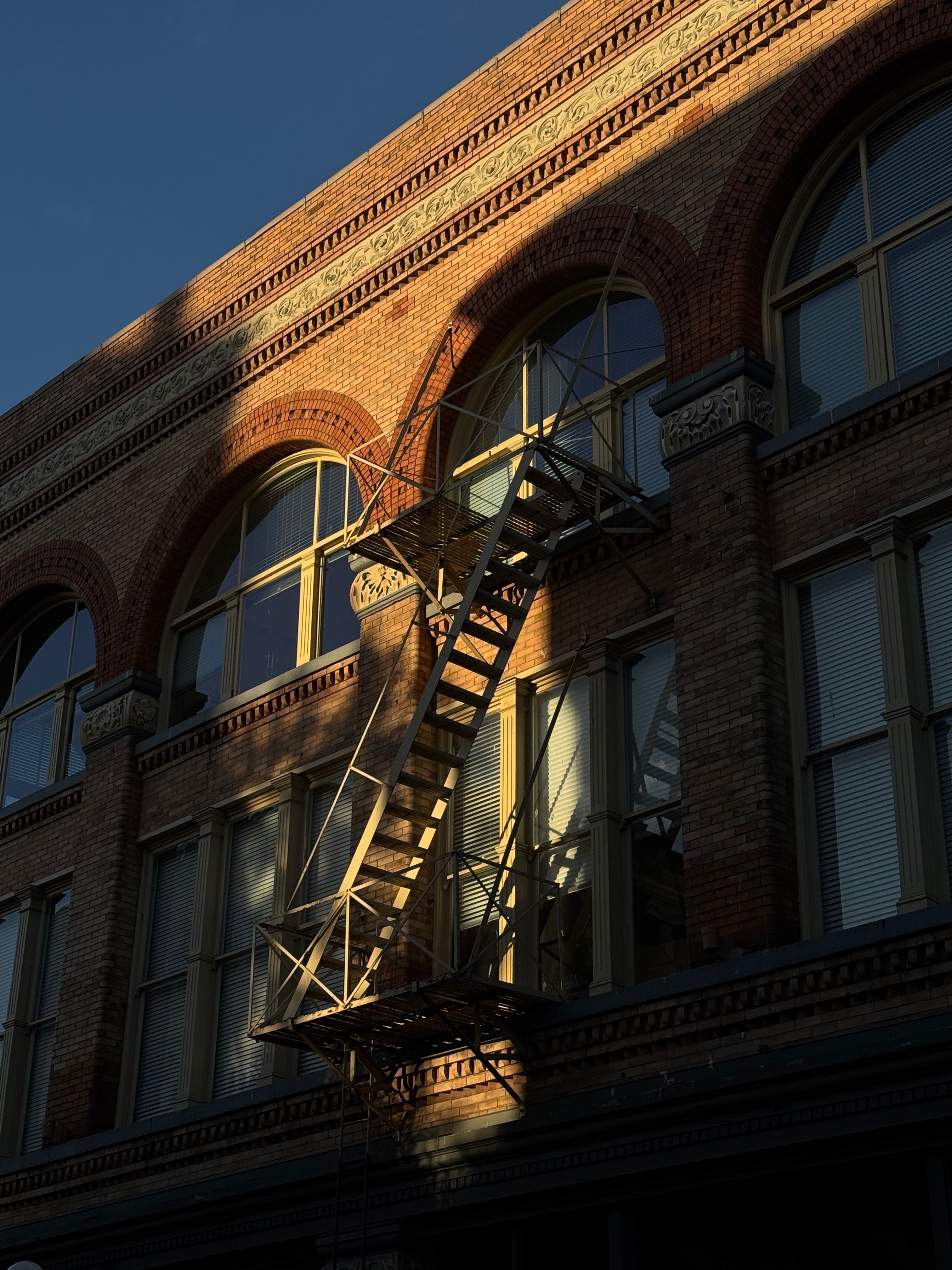 Historic Brick Building with Fire Escape Shadows · Free Stock Photo