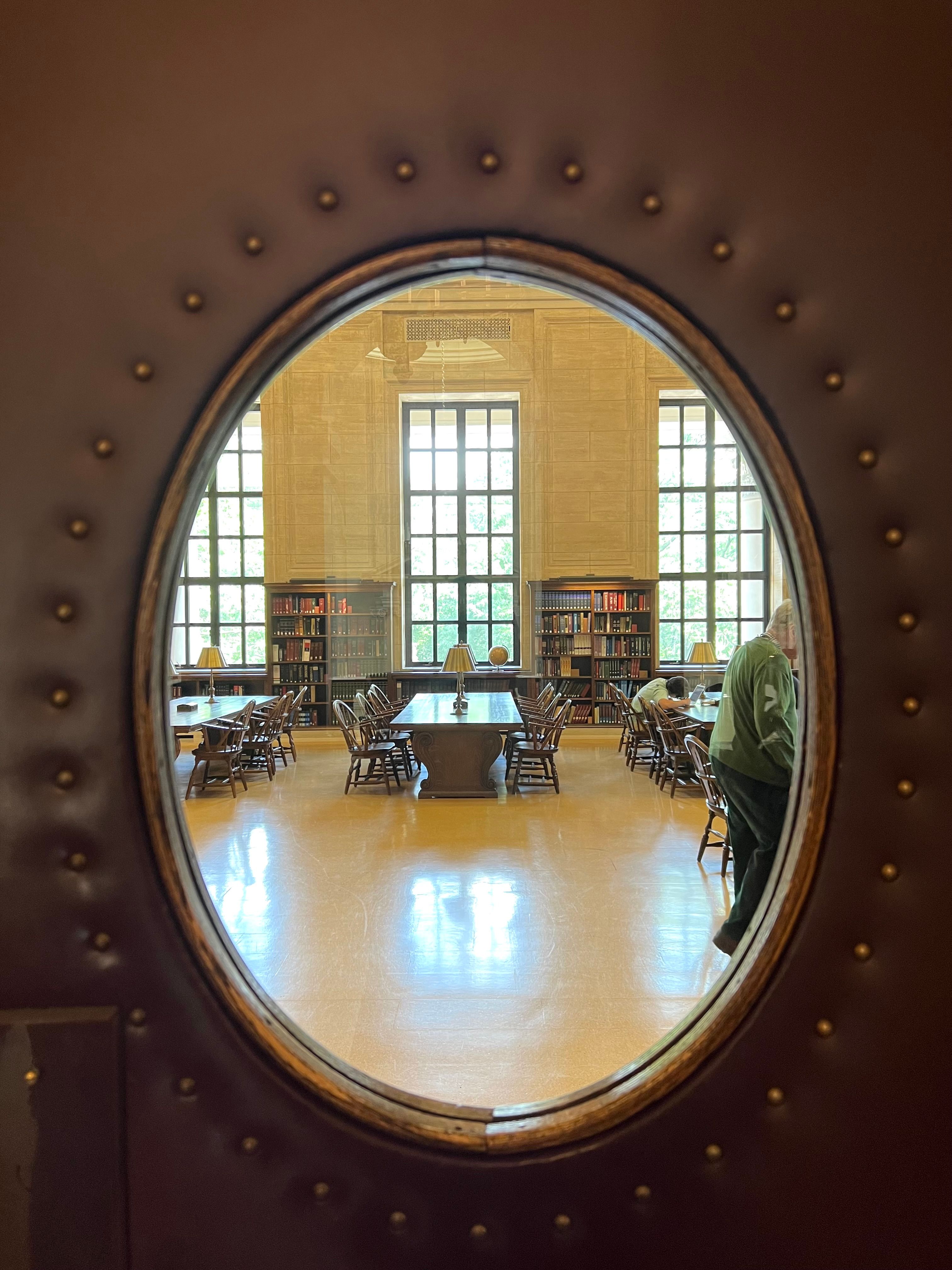 Academic Library Interior Viewed Through Oval Window · Free Stock Photo