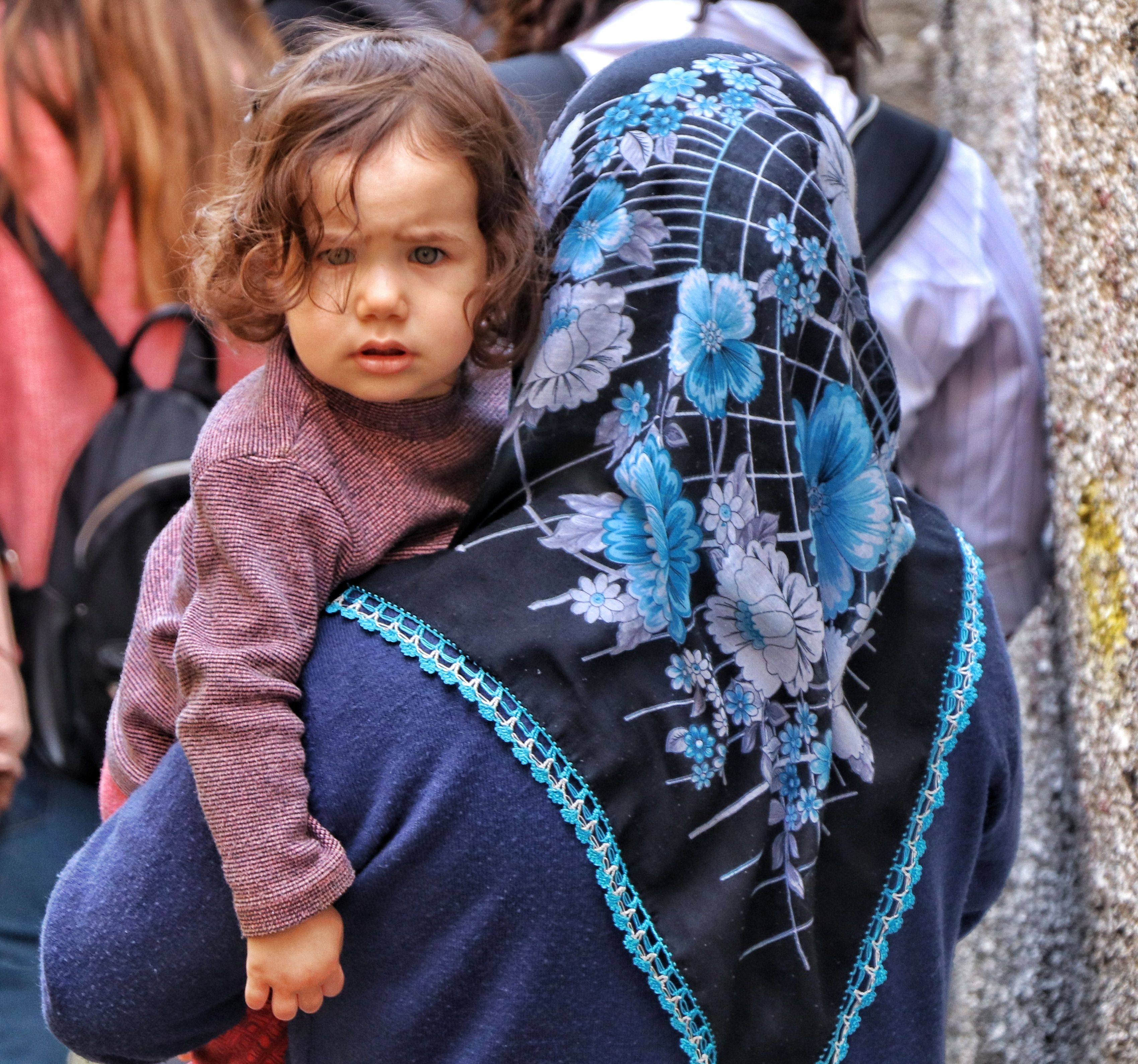 Mother Carrying Child in Vibrant Street Scene · Free Stock Photo