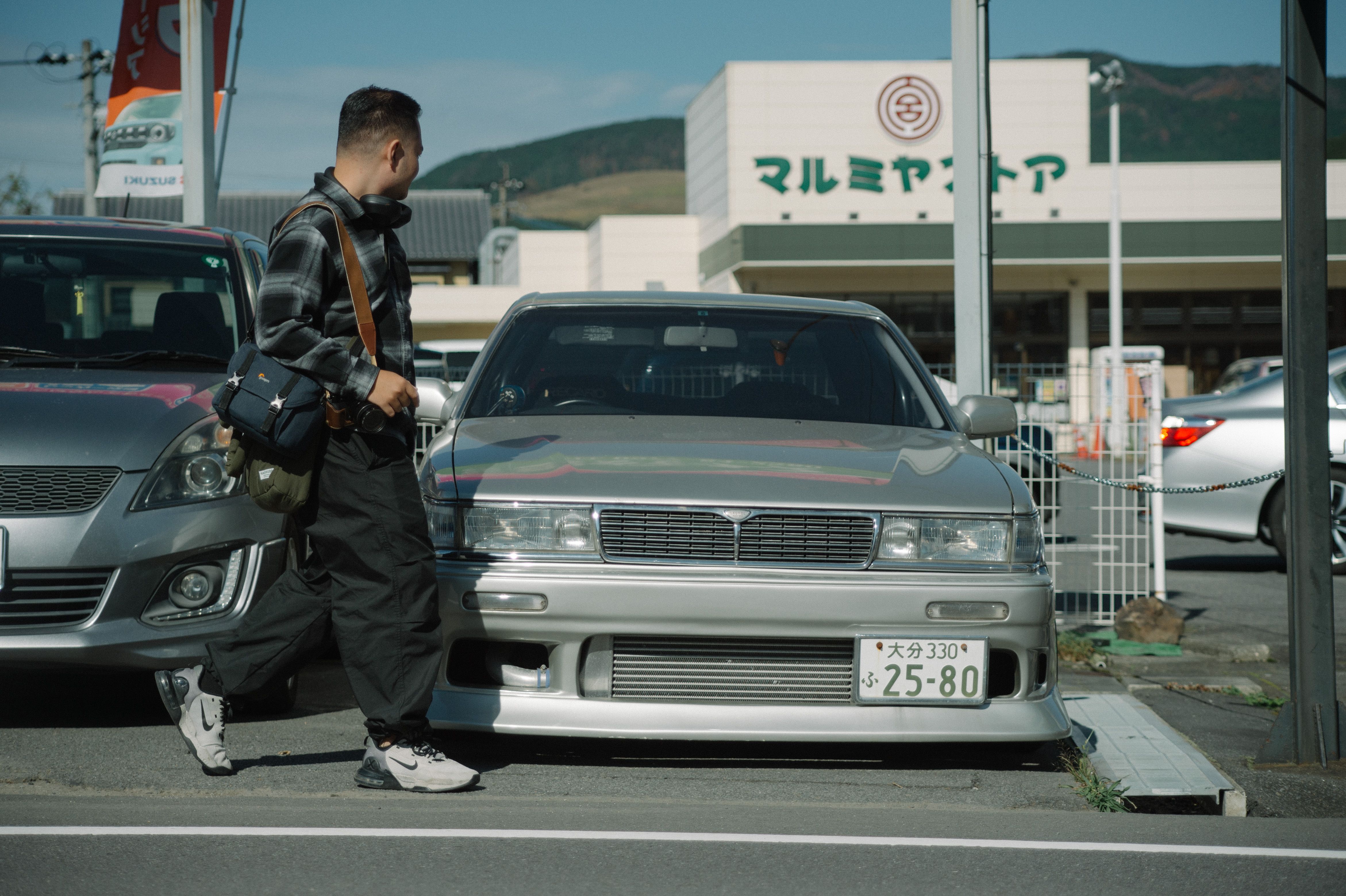 Man in Parking Lot Near Japanese Storefront · Free Stock Photo