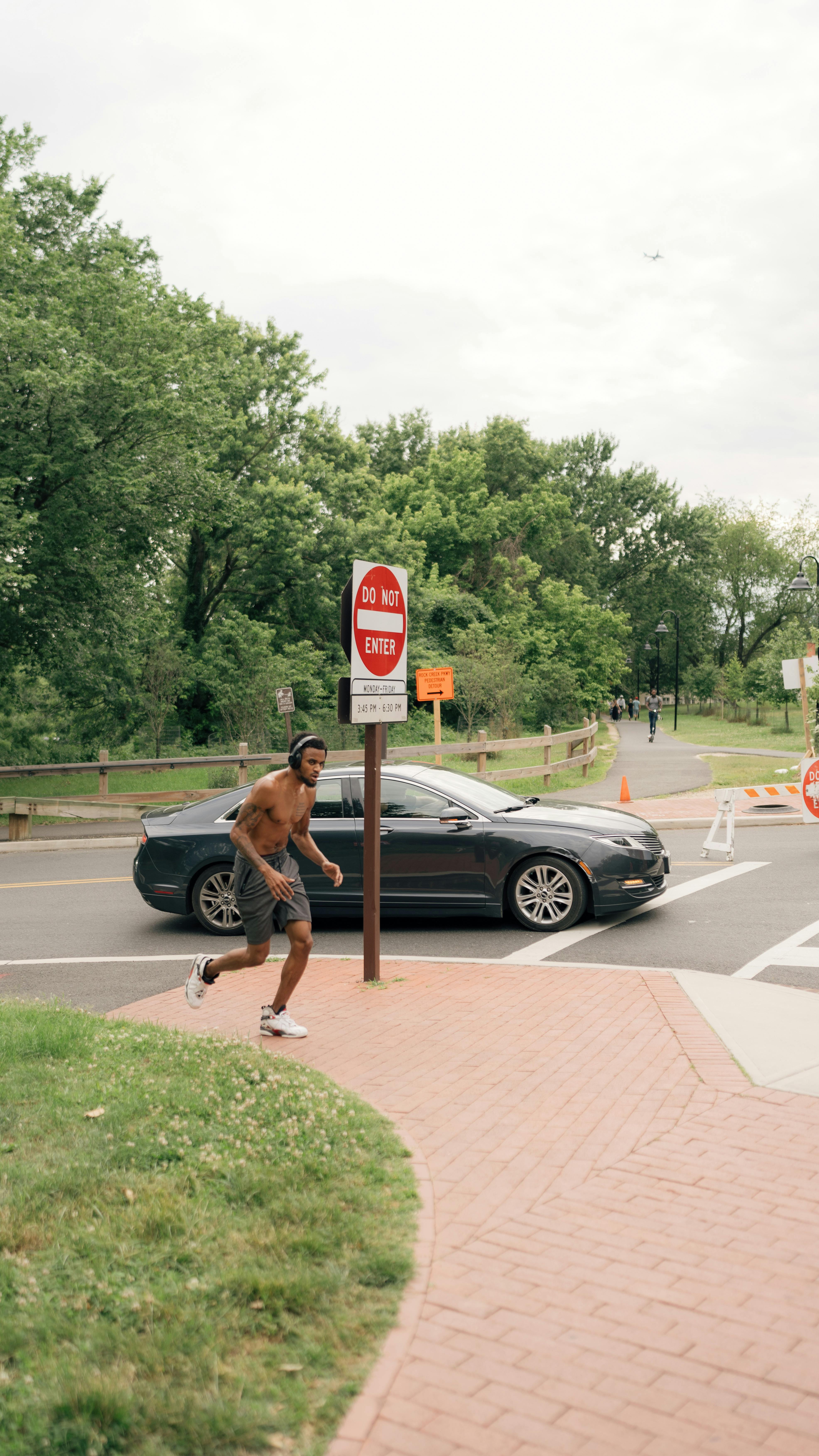 Man Jogging in Urban Park with Road Sign · Free Stock Photo