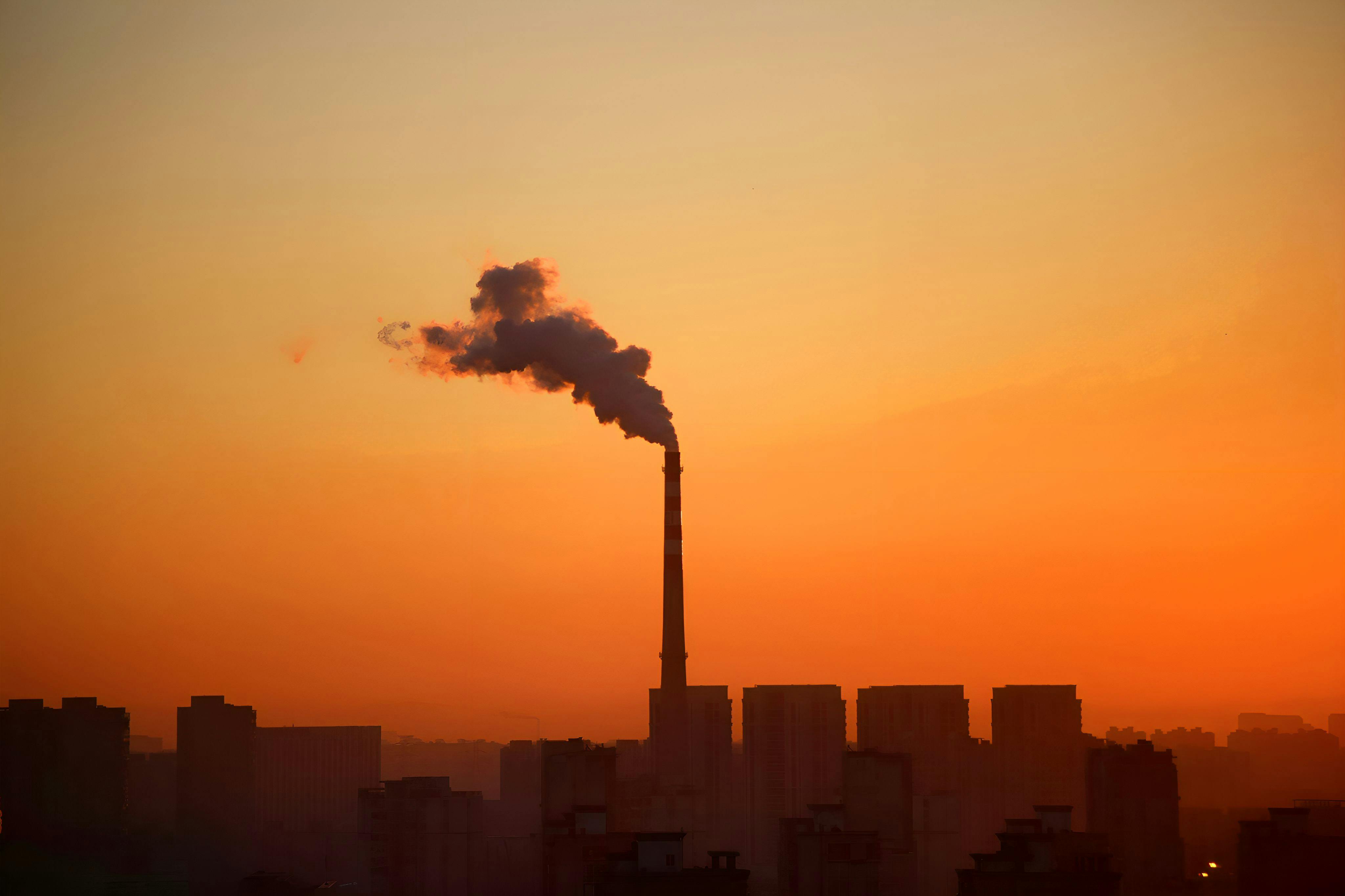 Industrial Smokestack Against a Vibrant Sunset Sky · Free Stock Photo