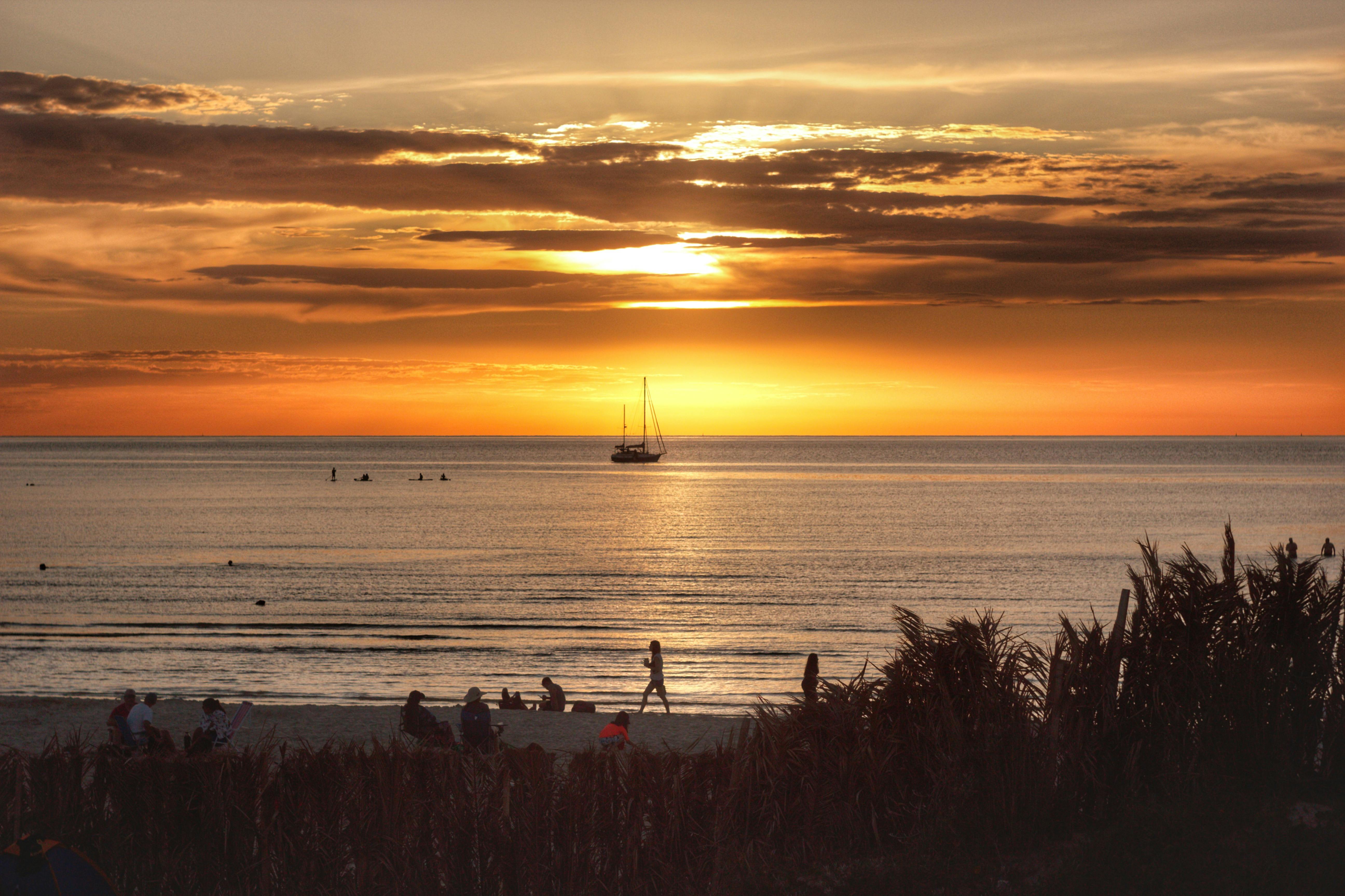 Tranquil Beach Sunset with Silhouetted Sailboat · Free Stock Photo