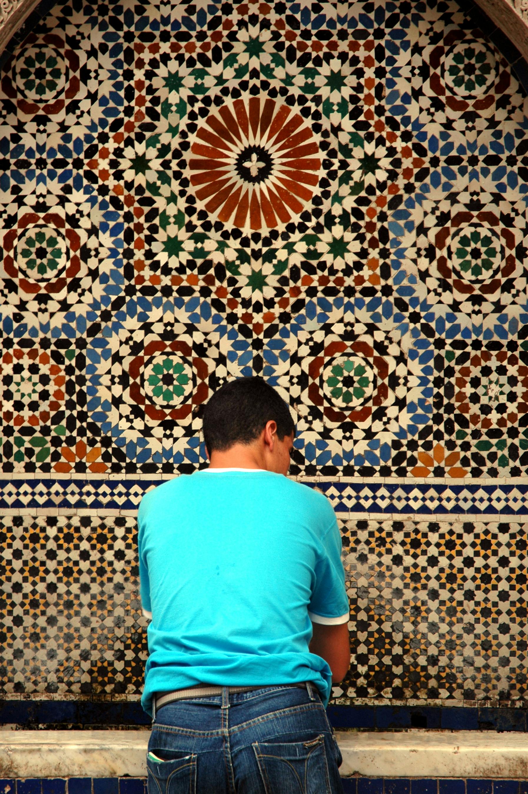 Man in Fès before Moroccan tile mosaic backdrop · Free Stock Photo