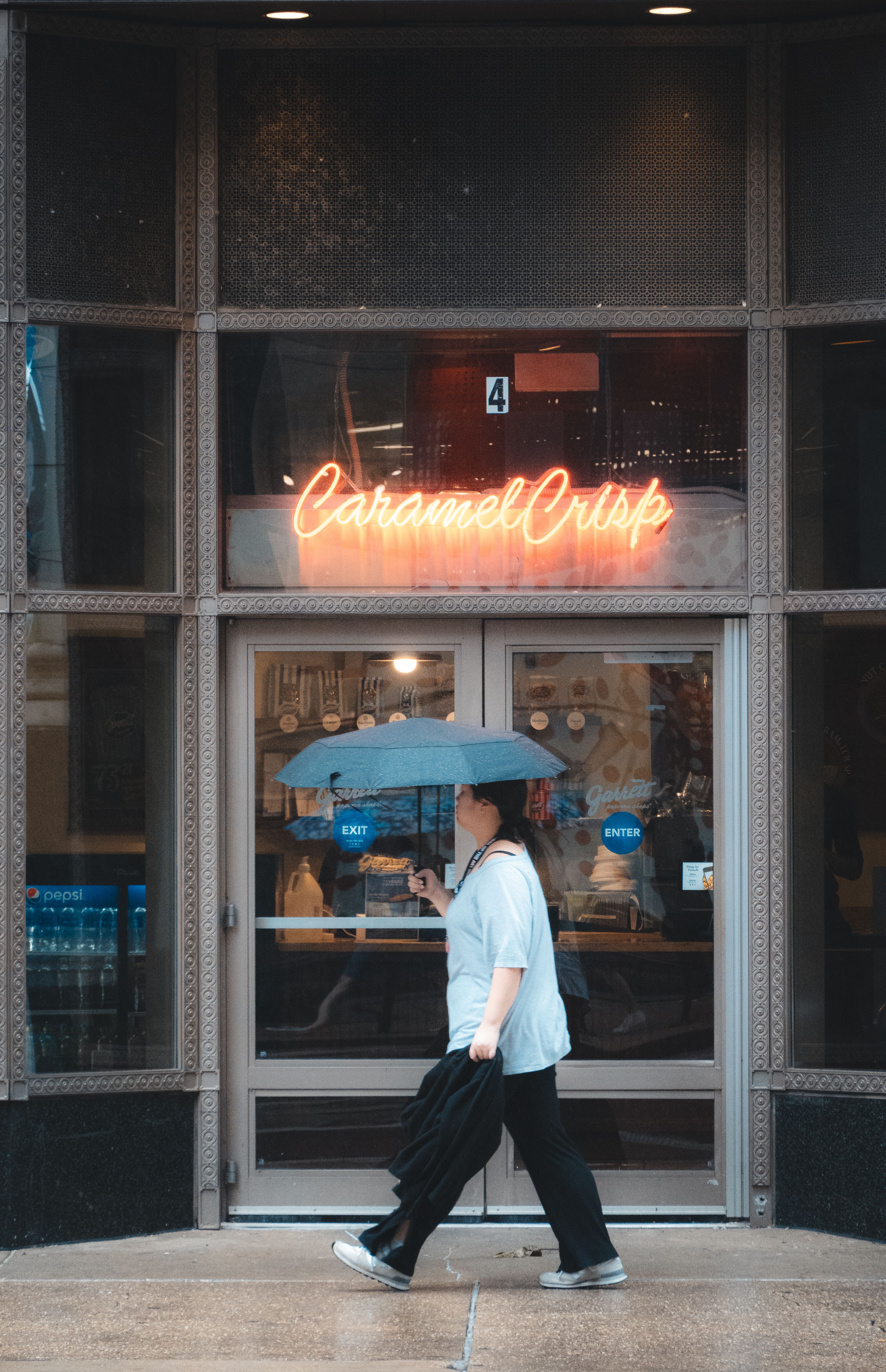 Umbrella Walk Past Caramel Crisp Storefront · Free Stock Photo