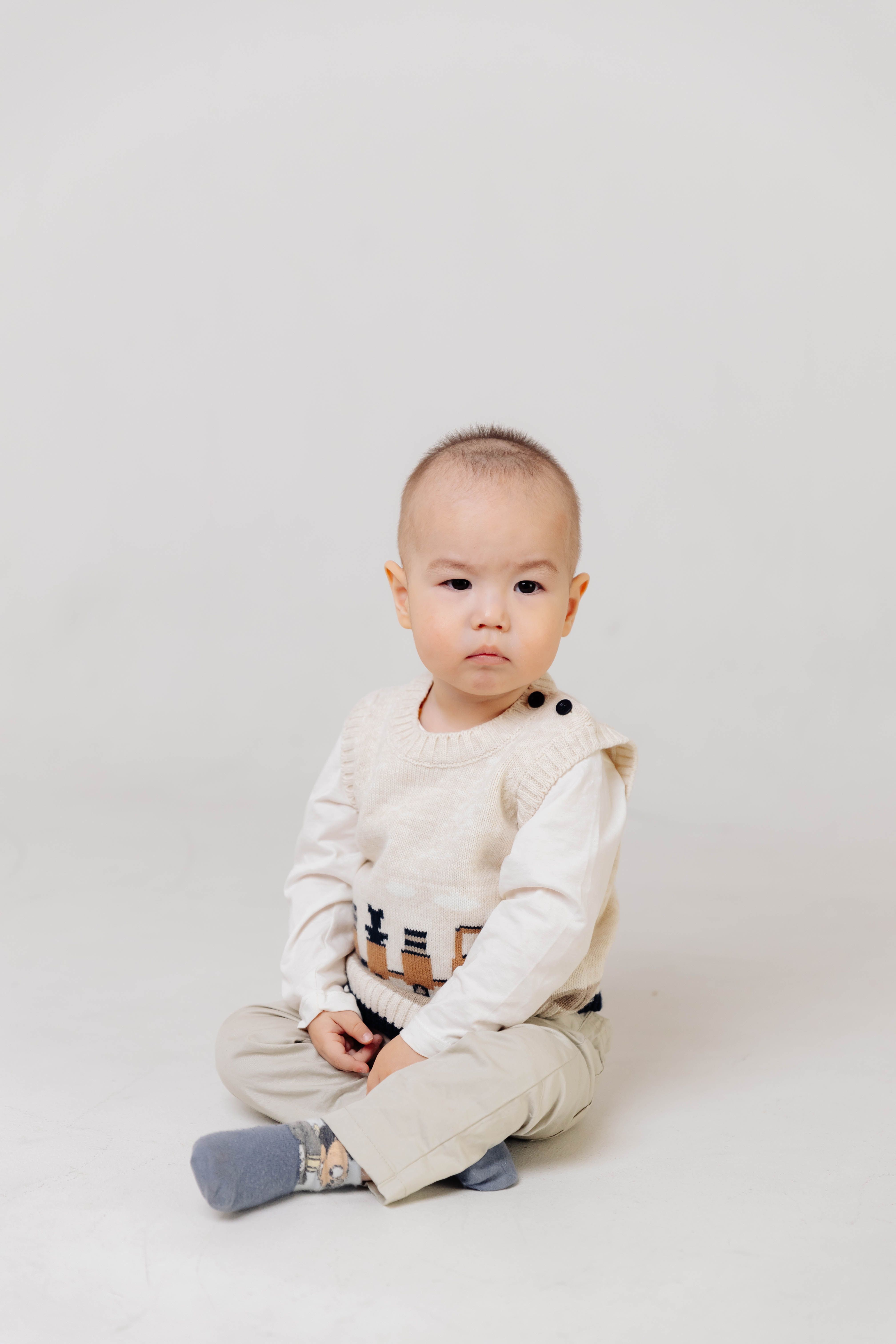 Adorable Baby Sitting on White Background · Free Stock Photo