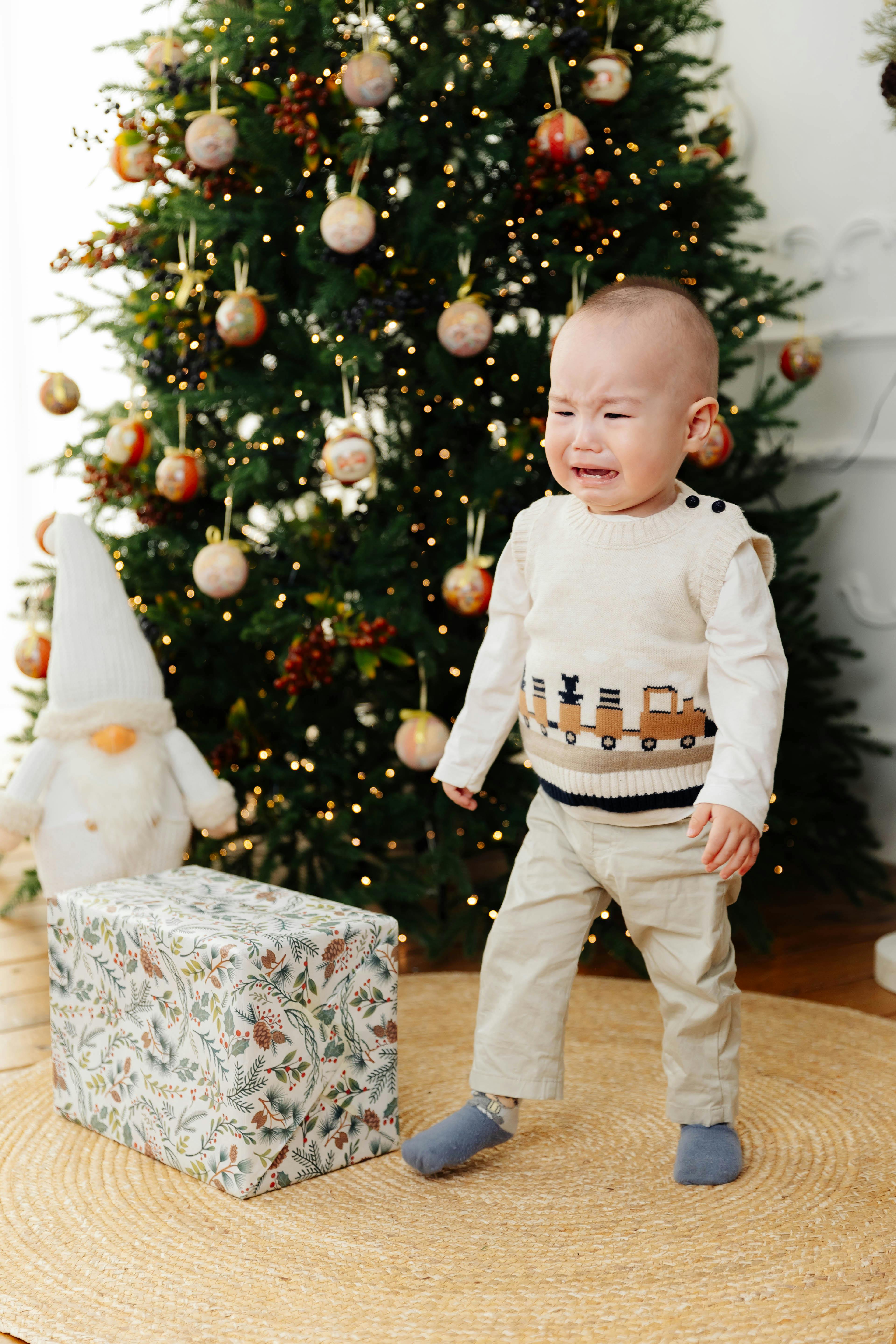 Crying Baby by Christmas Tree with Gift · Free Stock Photo