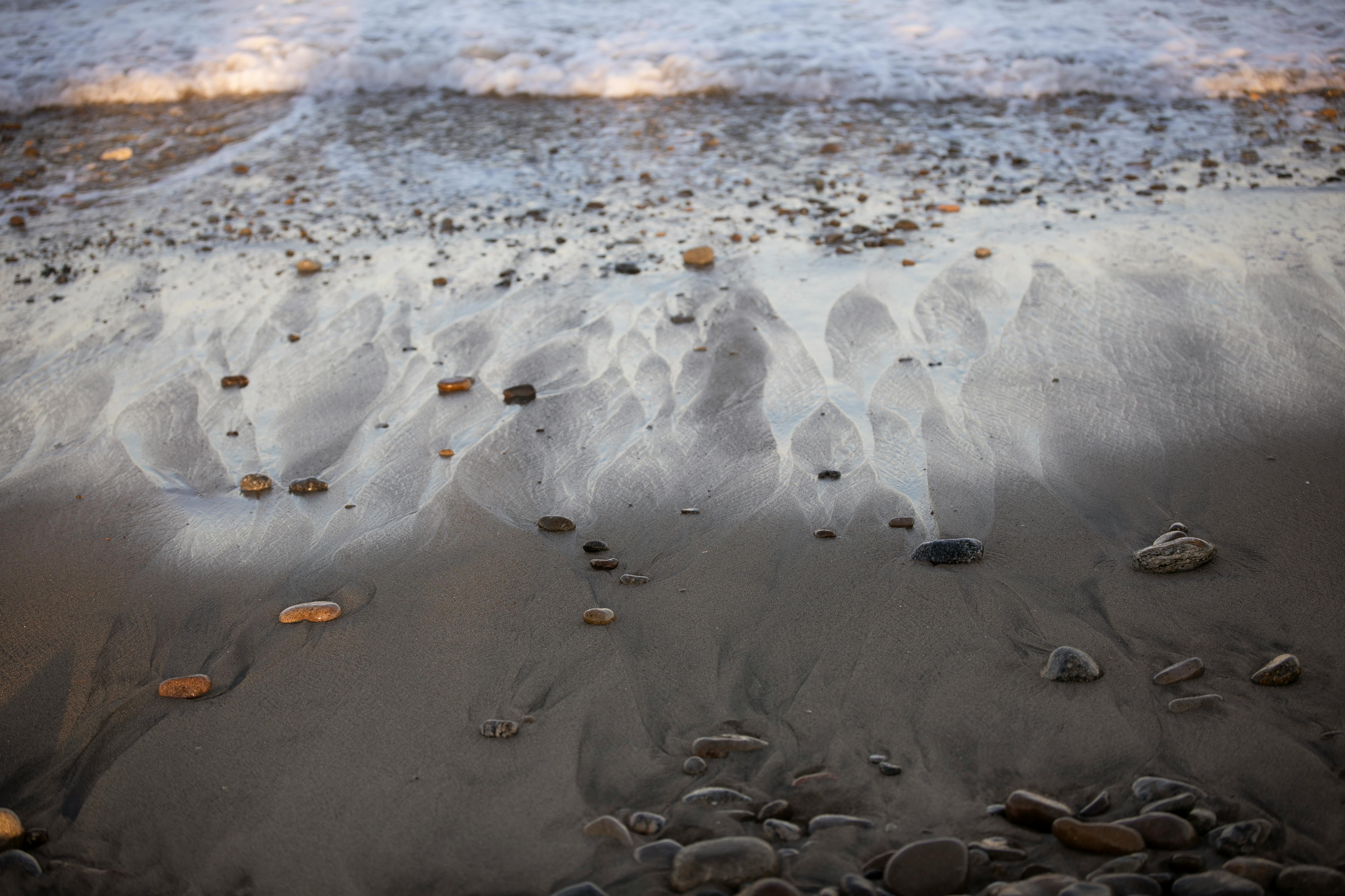 Serene Beach with Rippling Sand and Pebbles · Free Stock Photo