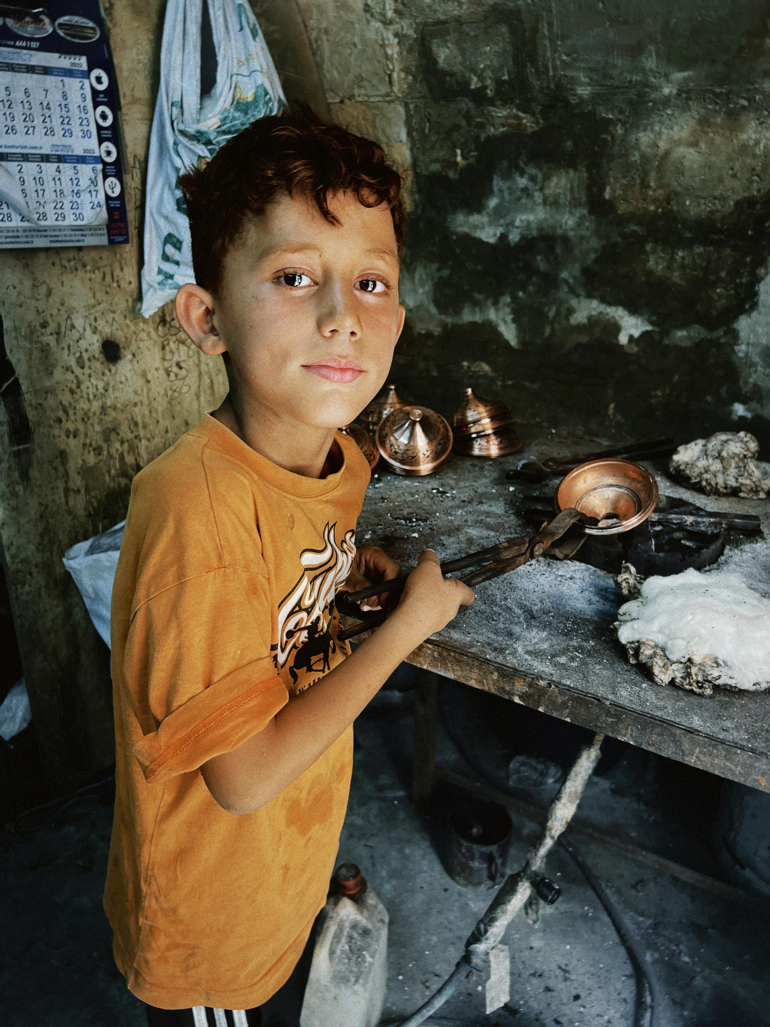 Young boy crafting metal tools in workshop · Free Stock Photo