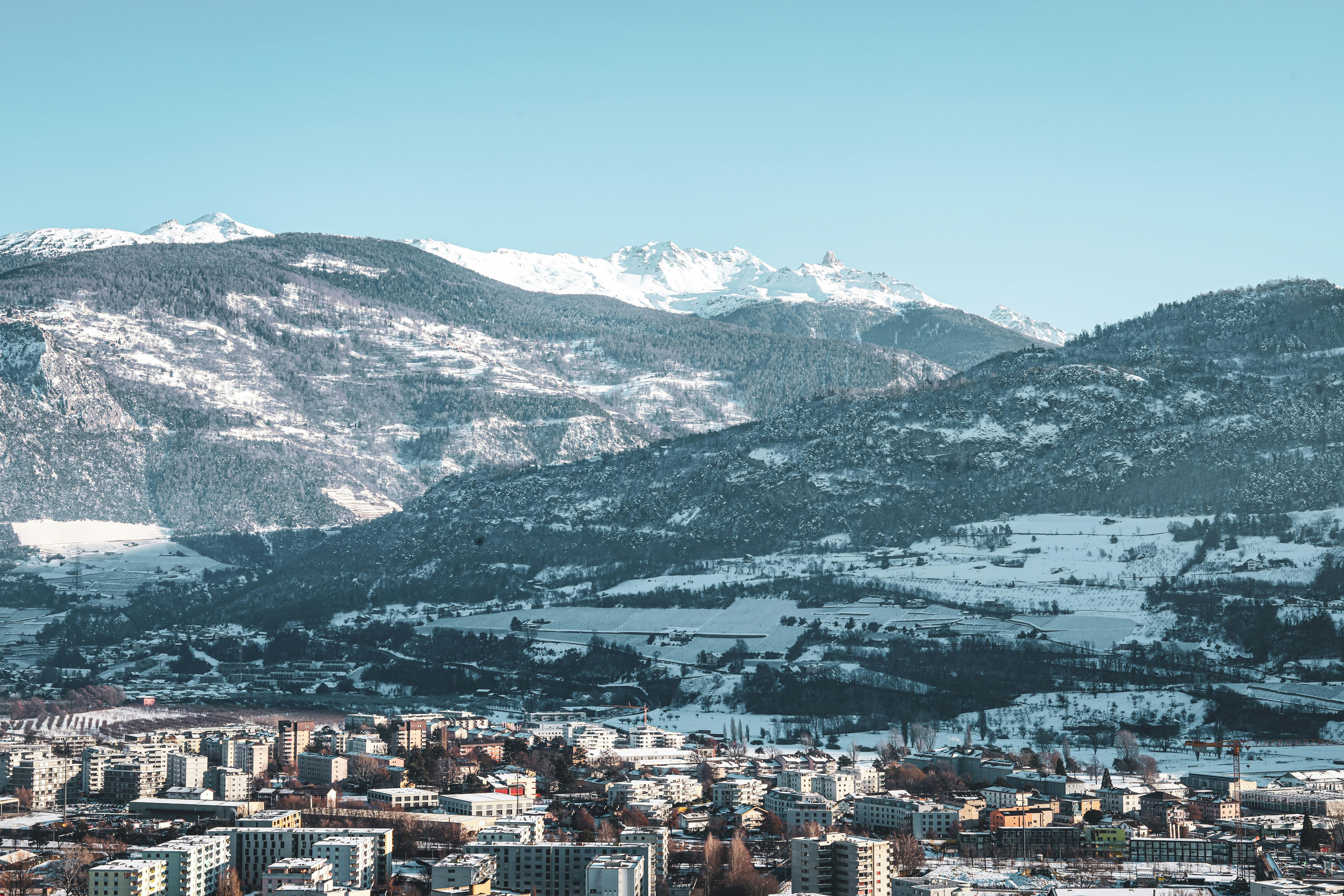 Snow-Capped Mountains Overlooking Scenic Alpine City · Free Stock Photo
