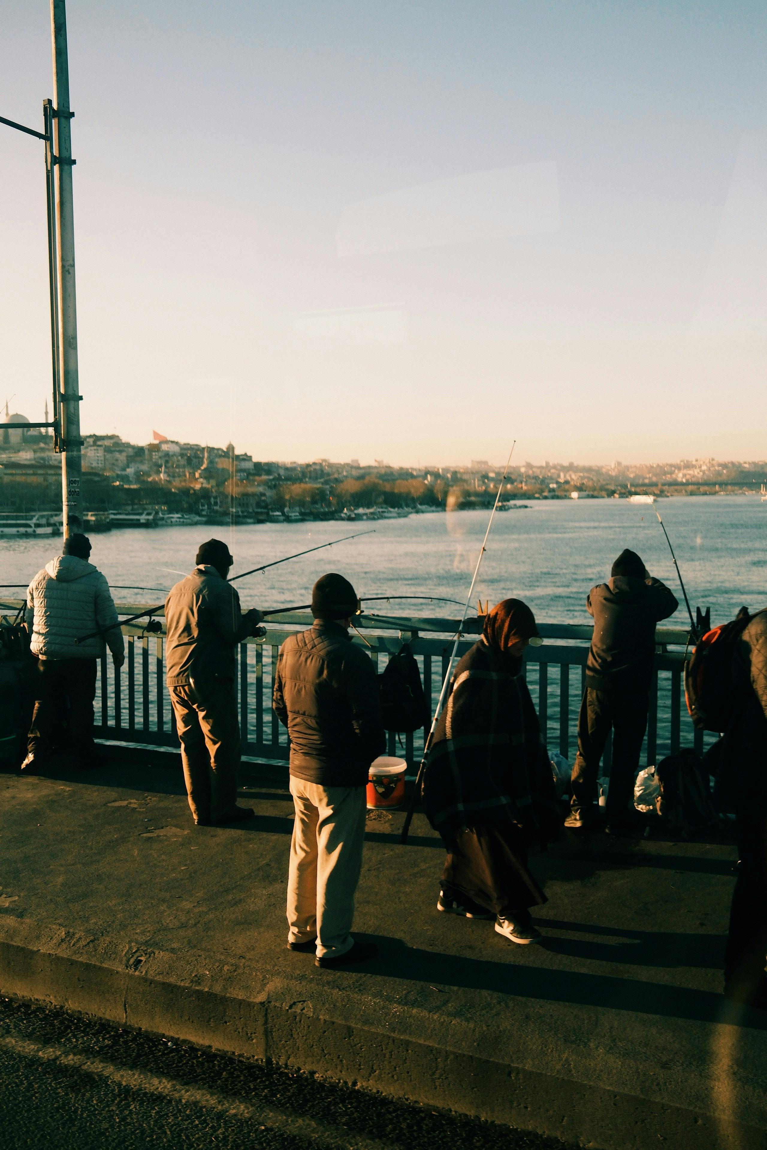 Grupo De Personas Pescando En Un Puente Al Atardecer · Foto de stock ...