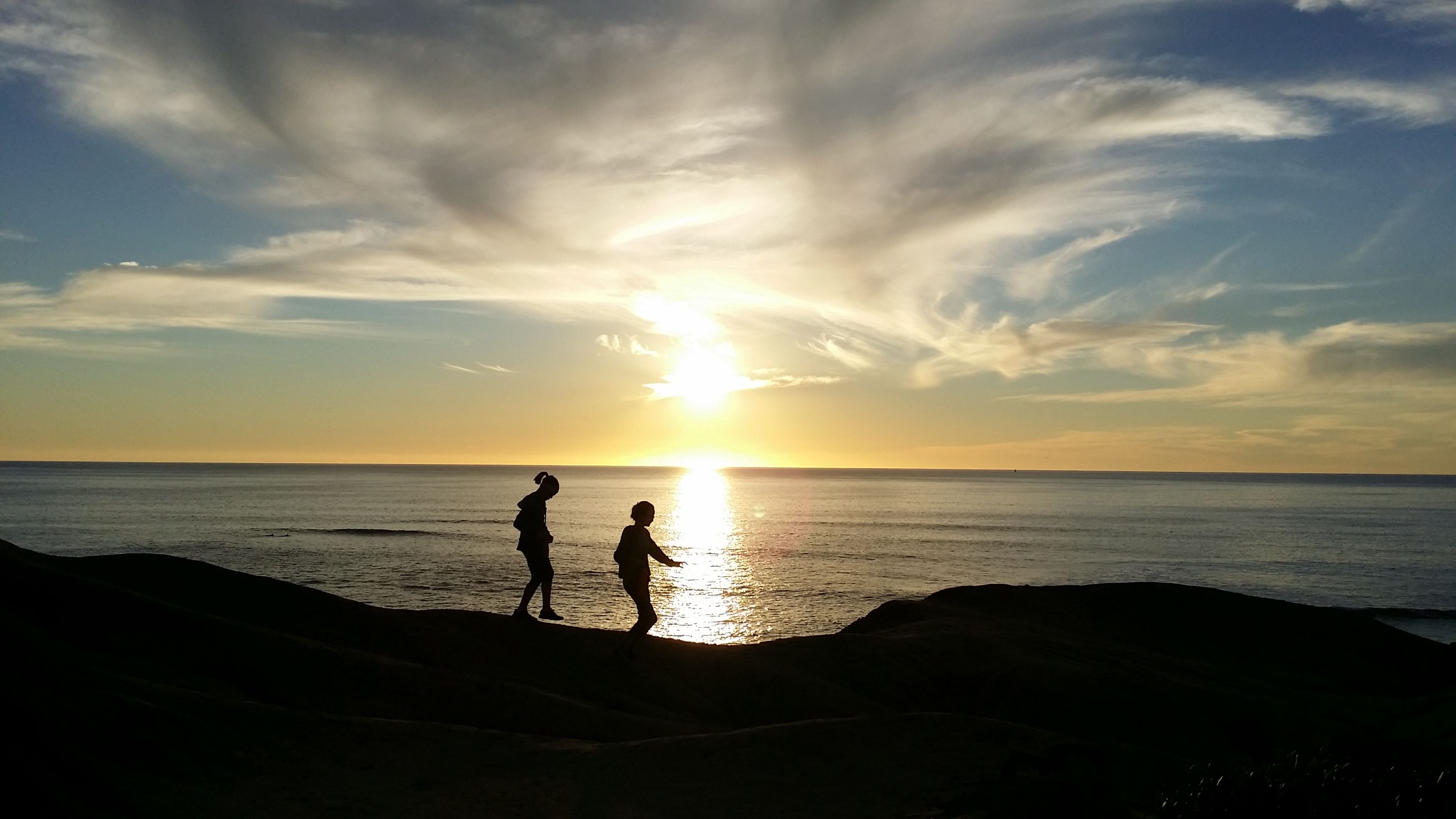 Silhouetted Sunset Walk Along Scenic Coastline · Free Stock Photo