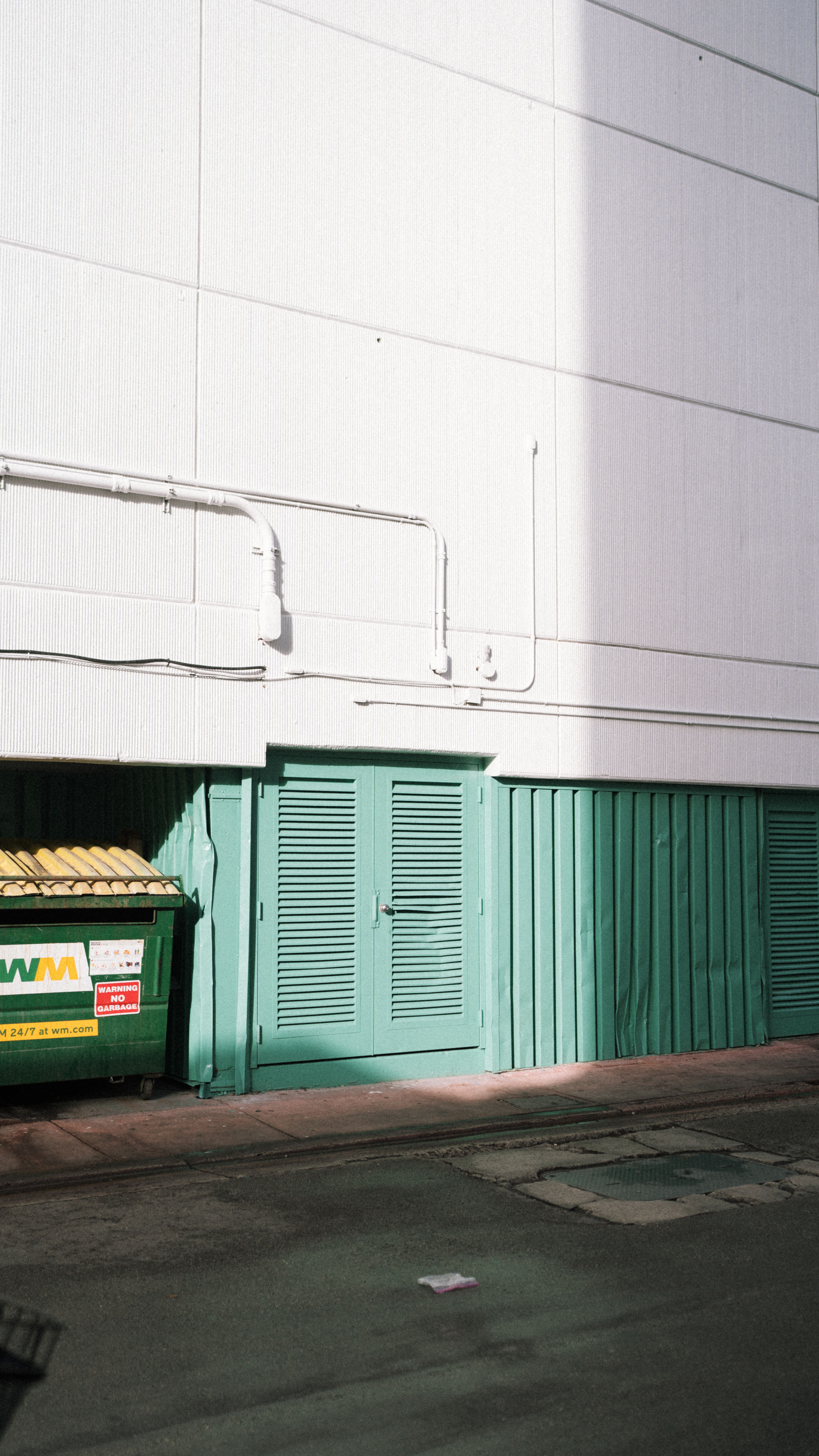 Urban Alleyway with Green Doors and Dumpster · Free Stock Photo
