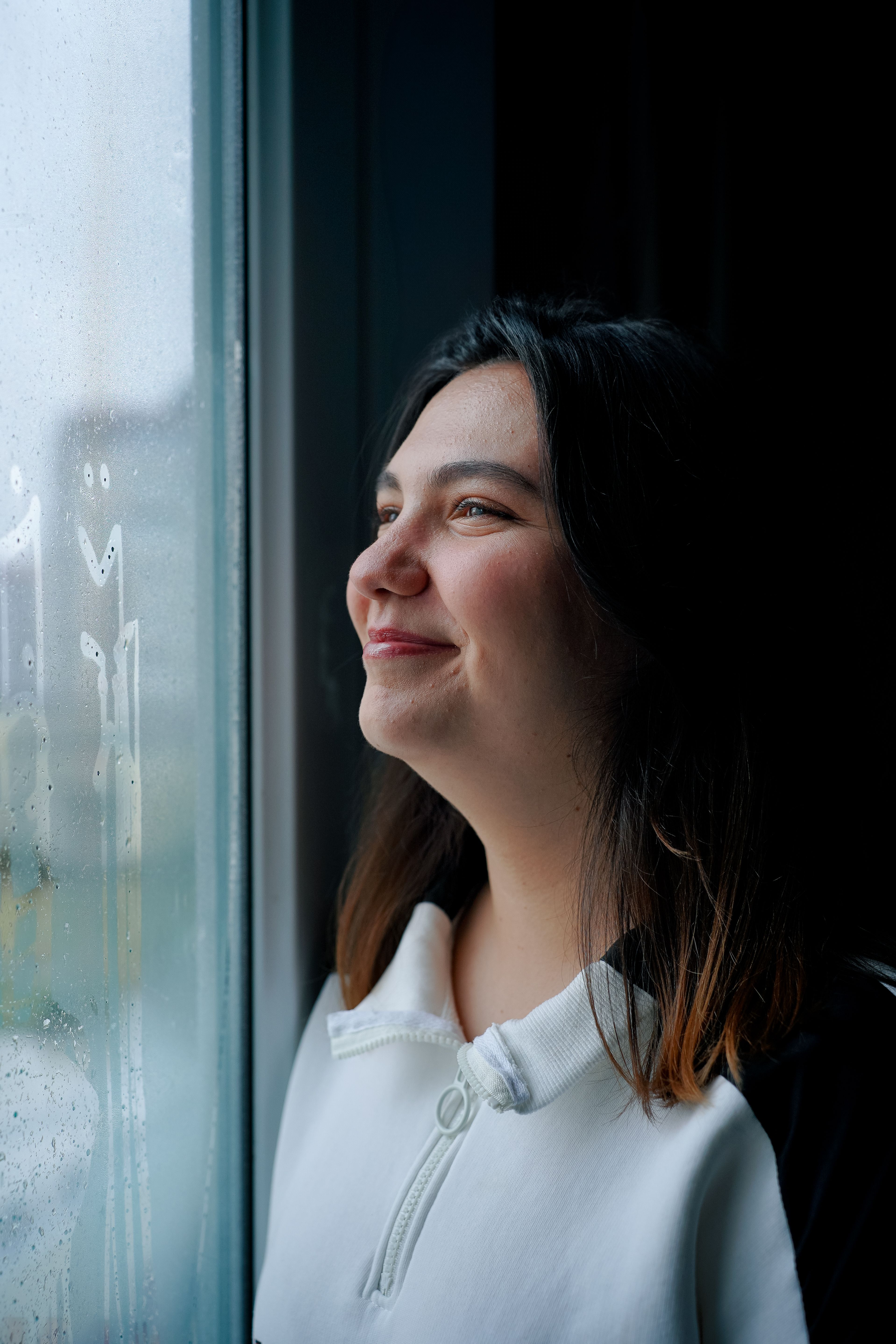 Woman Smiling Through Rainy Window Indoors · Free Stock Photo