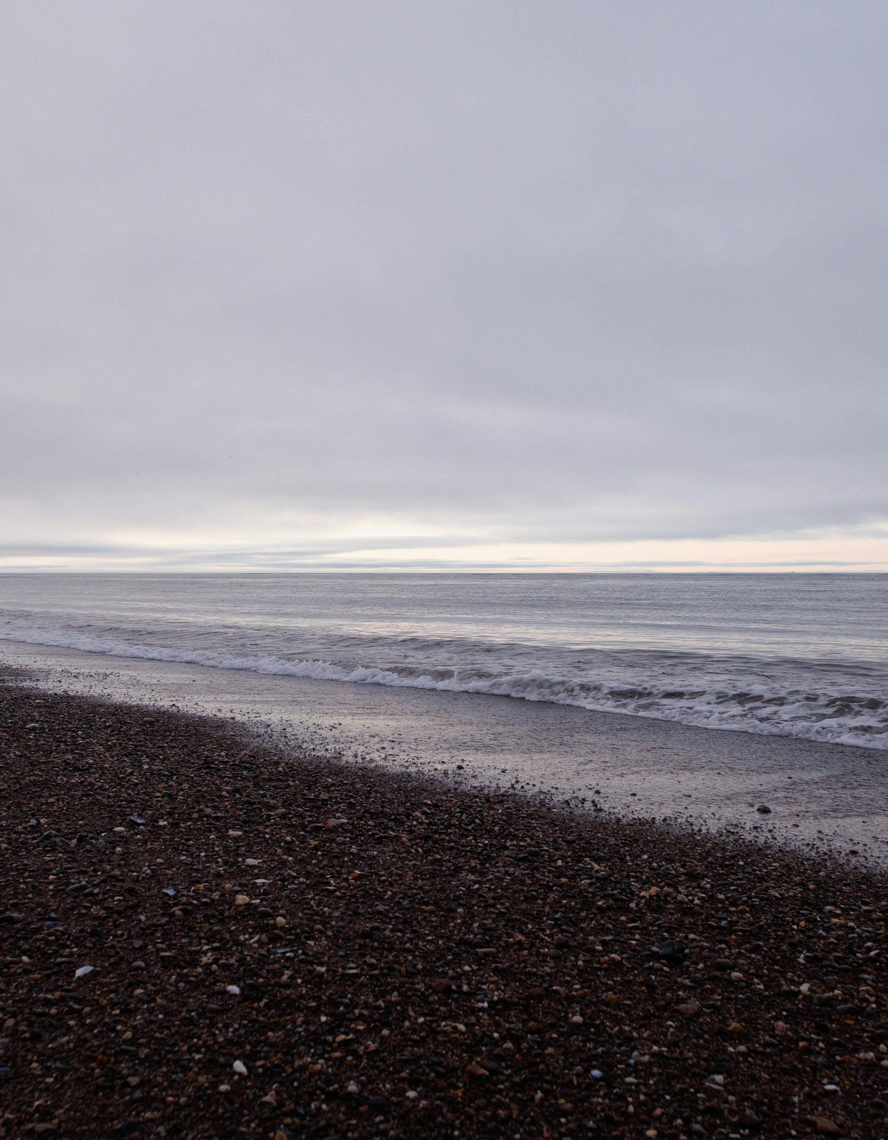 Tranquil Overcast Beach with Gentle Waves · Free Stock Photo