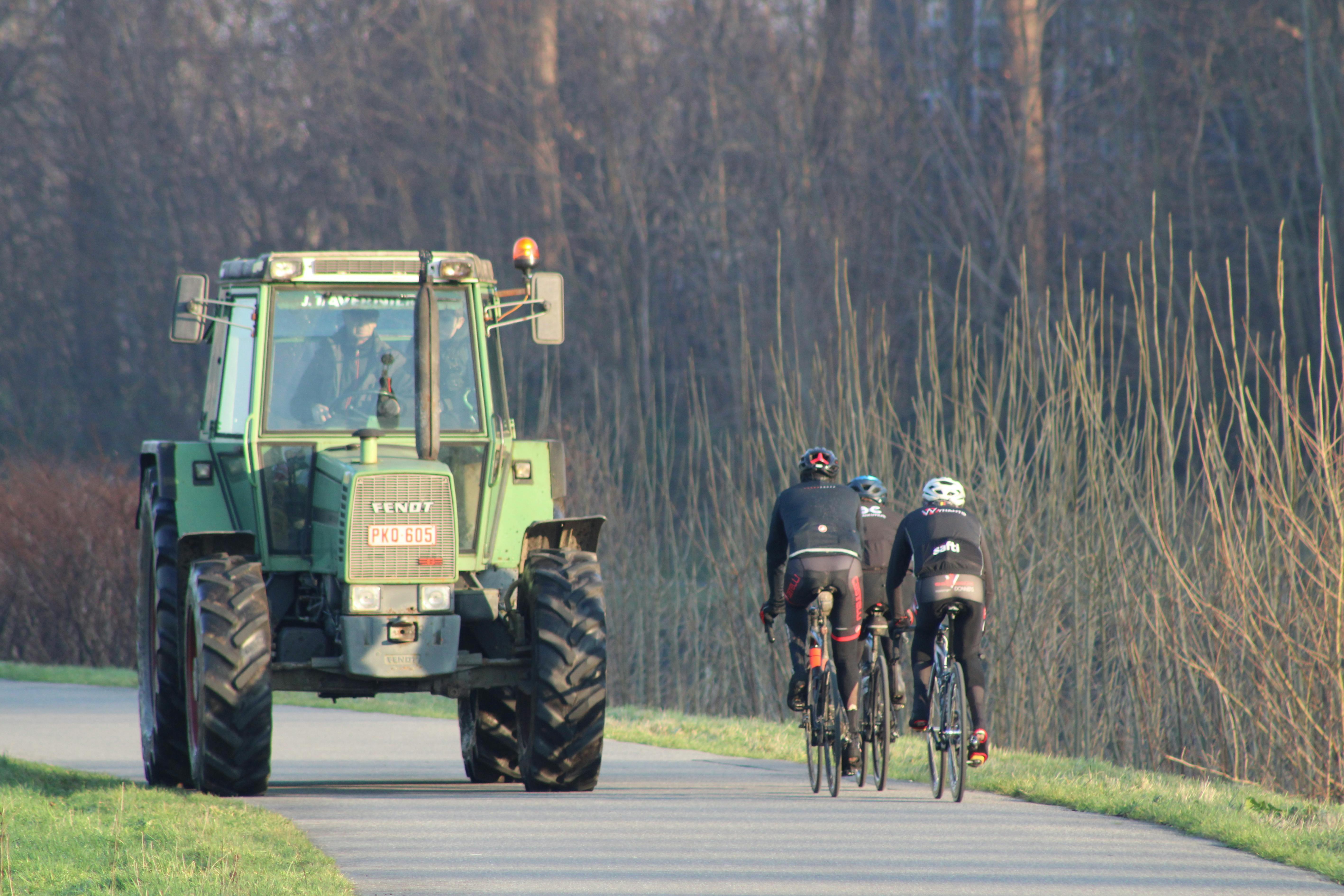 Cyclists Riding Alongside Tractor in Scenic Belgium · Free Stock Photo