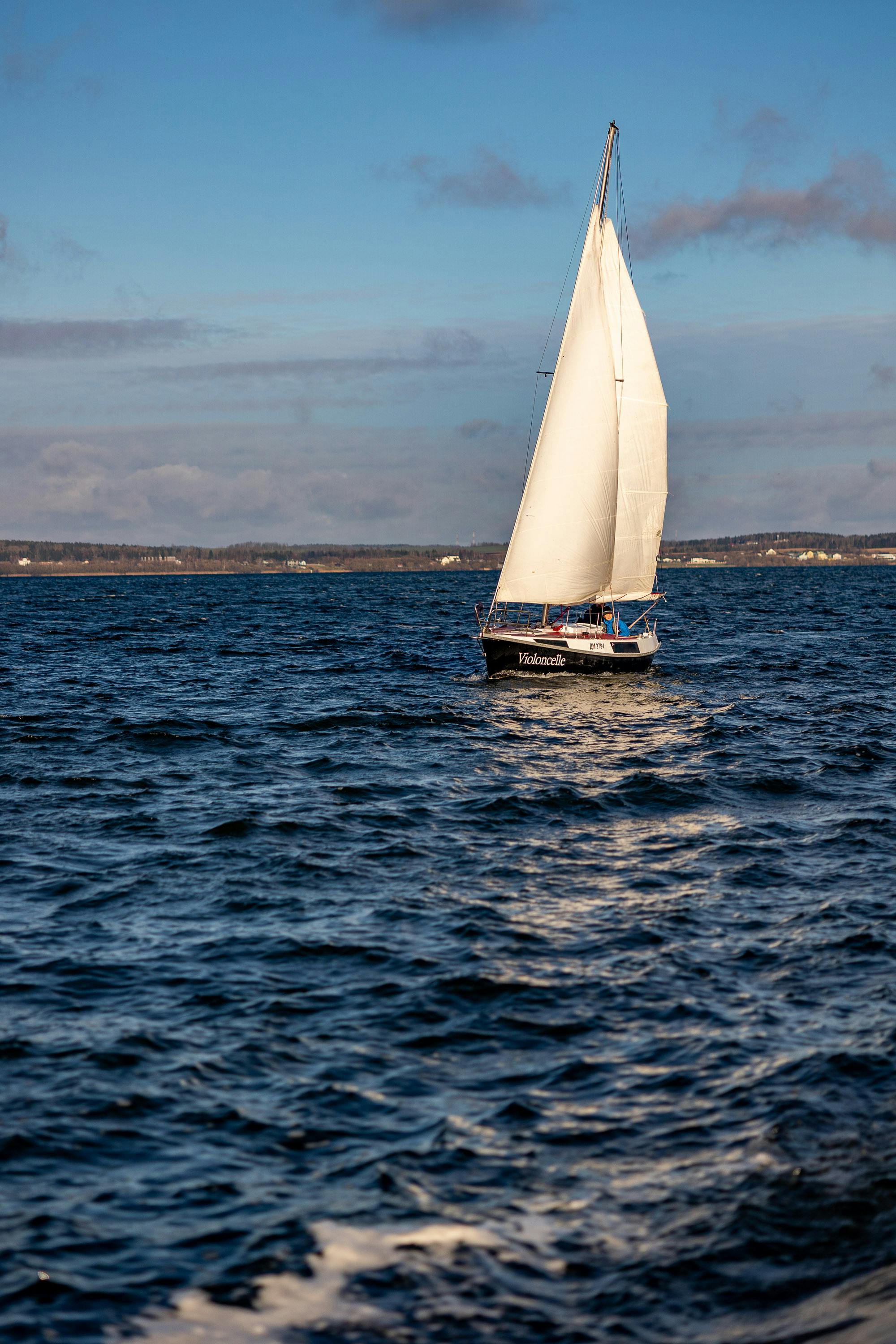 Sailboat Navigating Calm Waters Under Blue Skies · Free Stock Photo