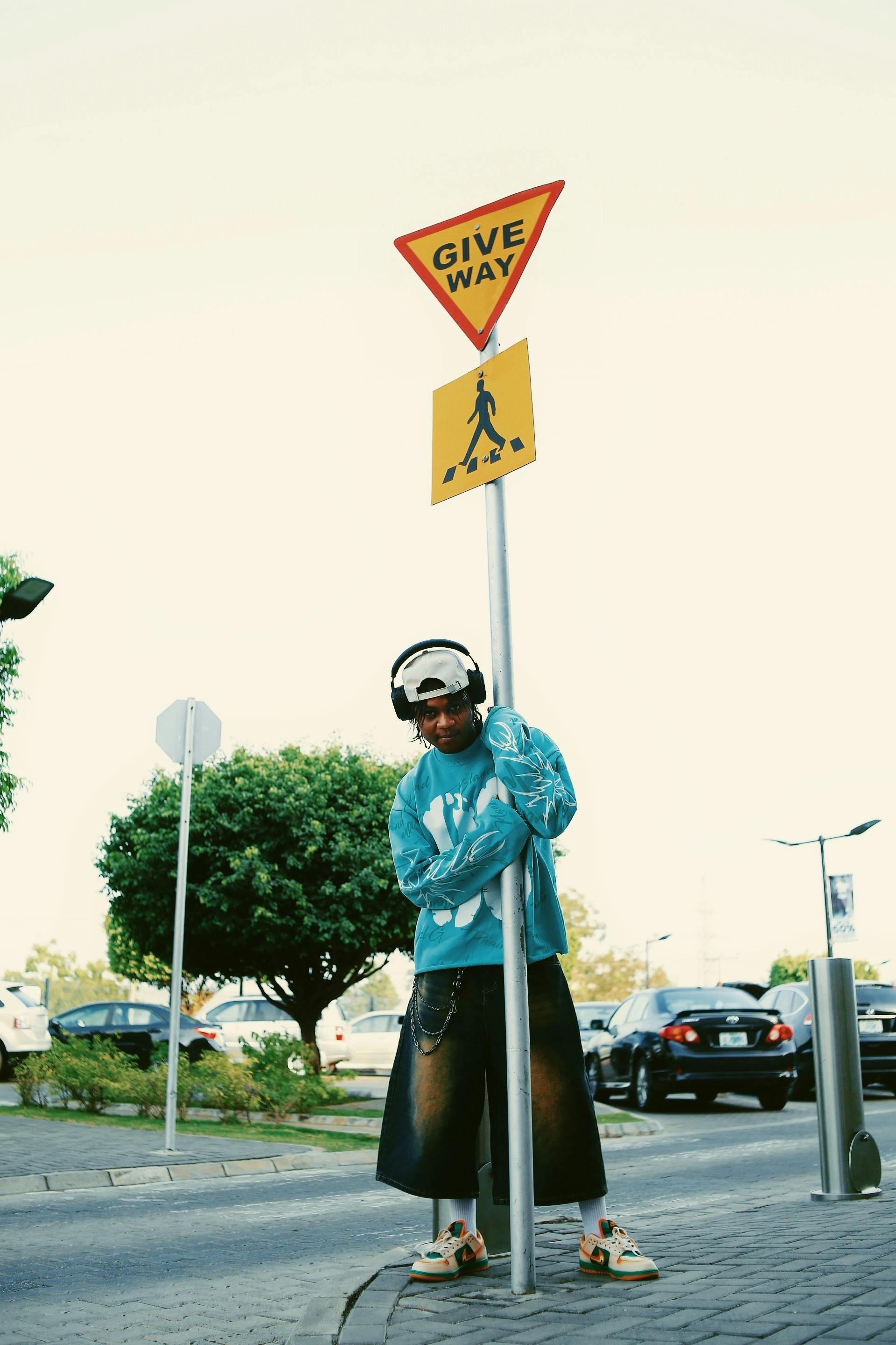 Stylish Person Leaning Against Give Way Sign in Abuja · Free Stock Photo