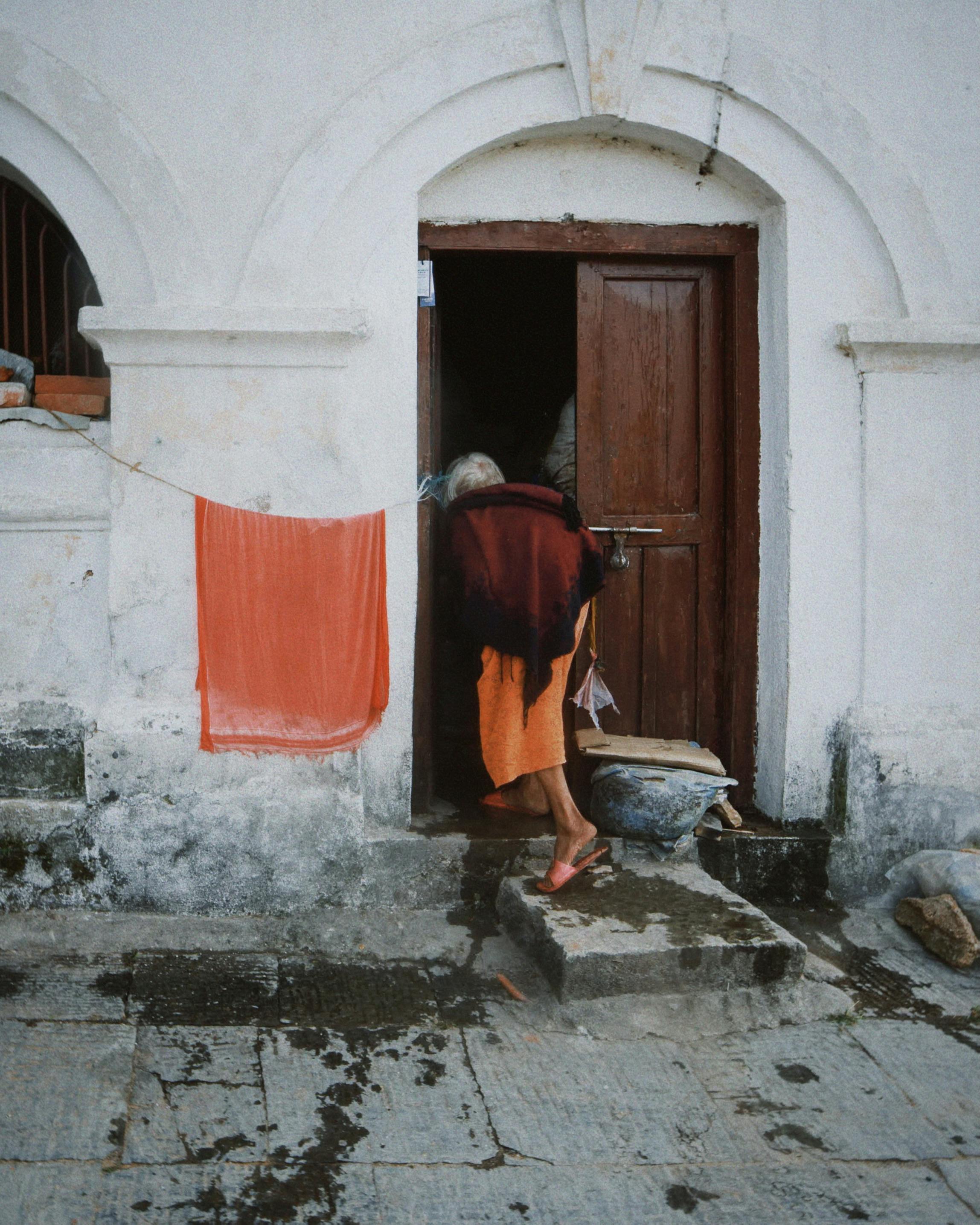 Monk Entering a Traditional Stone Building · Free Stock Photo